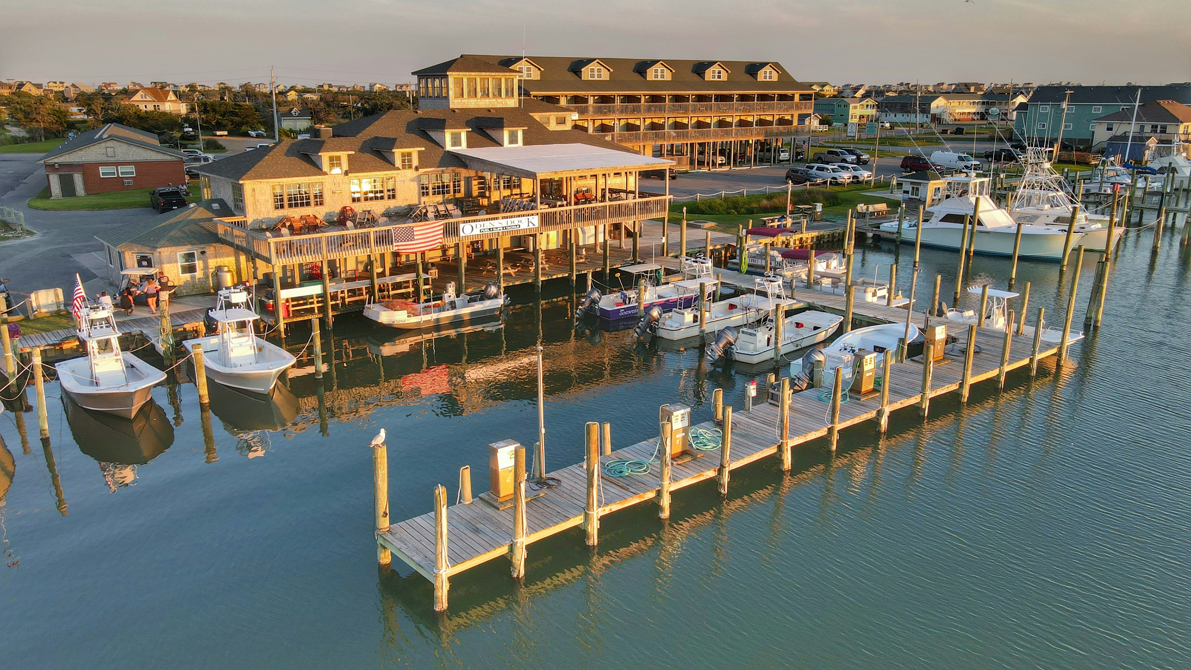 Boats docked at Oden's Dock marina in Hatteras Island, bathed in warm sunset light.