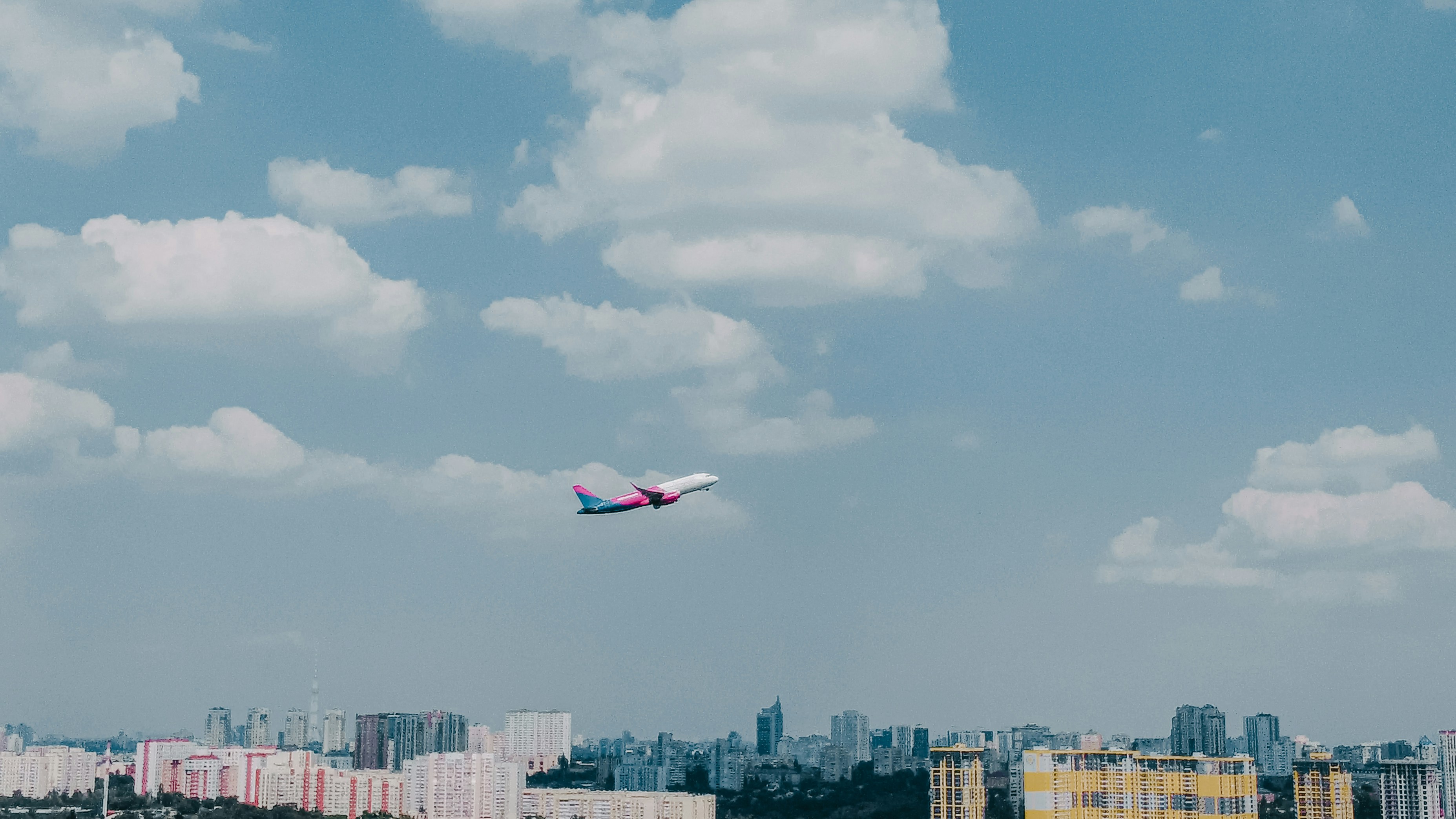 White and red plane flying over city buildings during daytime photo ...