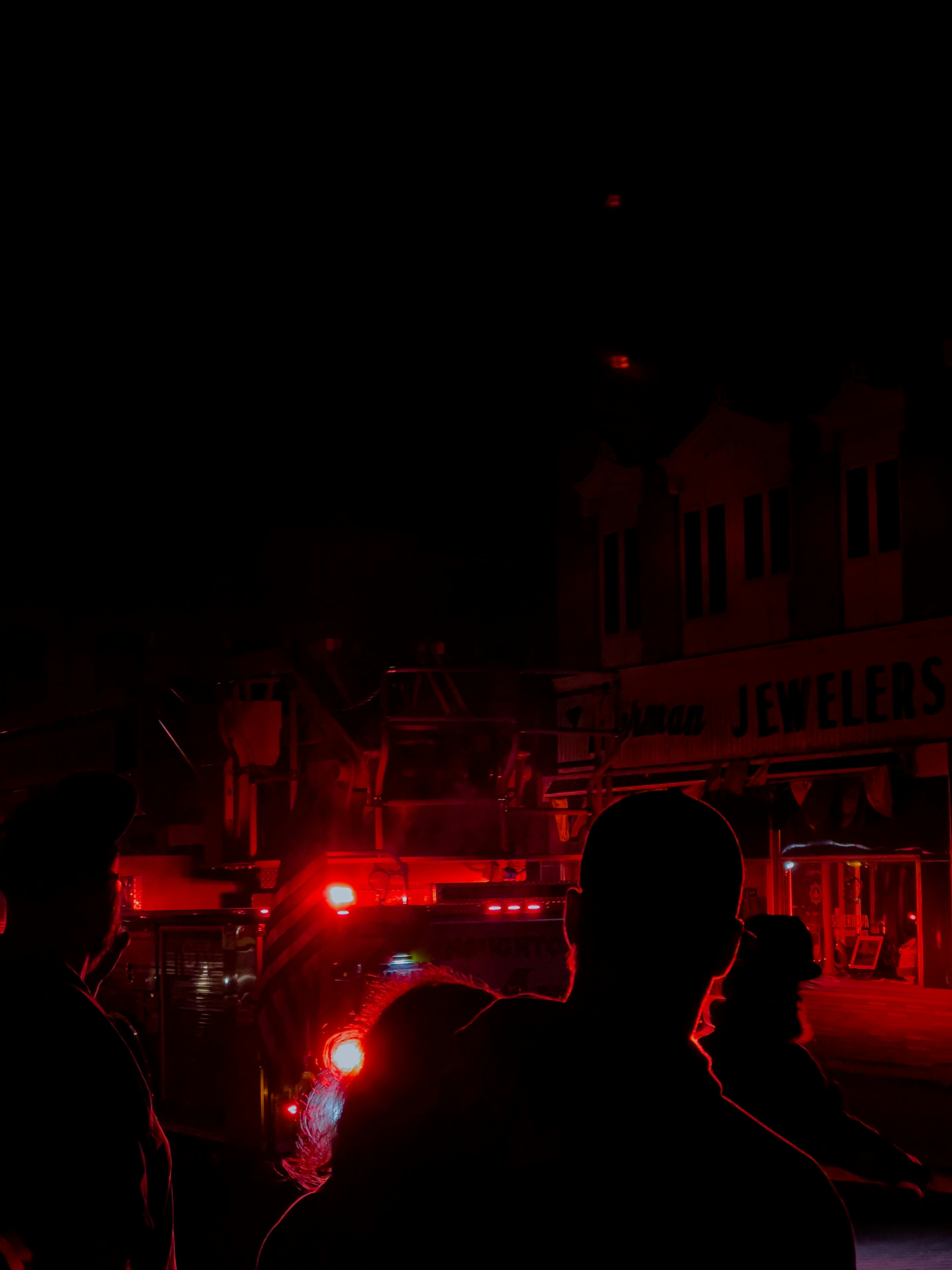 Crimson Sirens on a Dim Street: Silhouettes Beside a Fire Engine