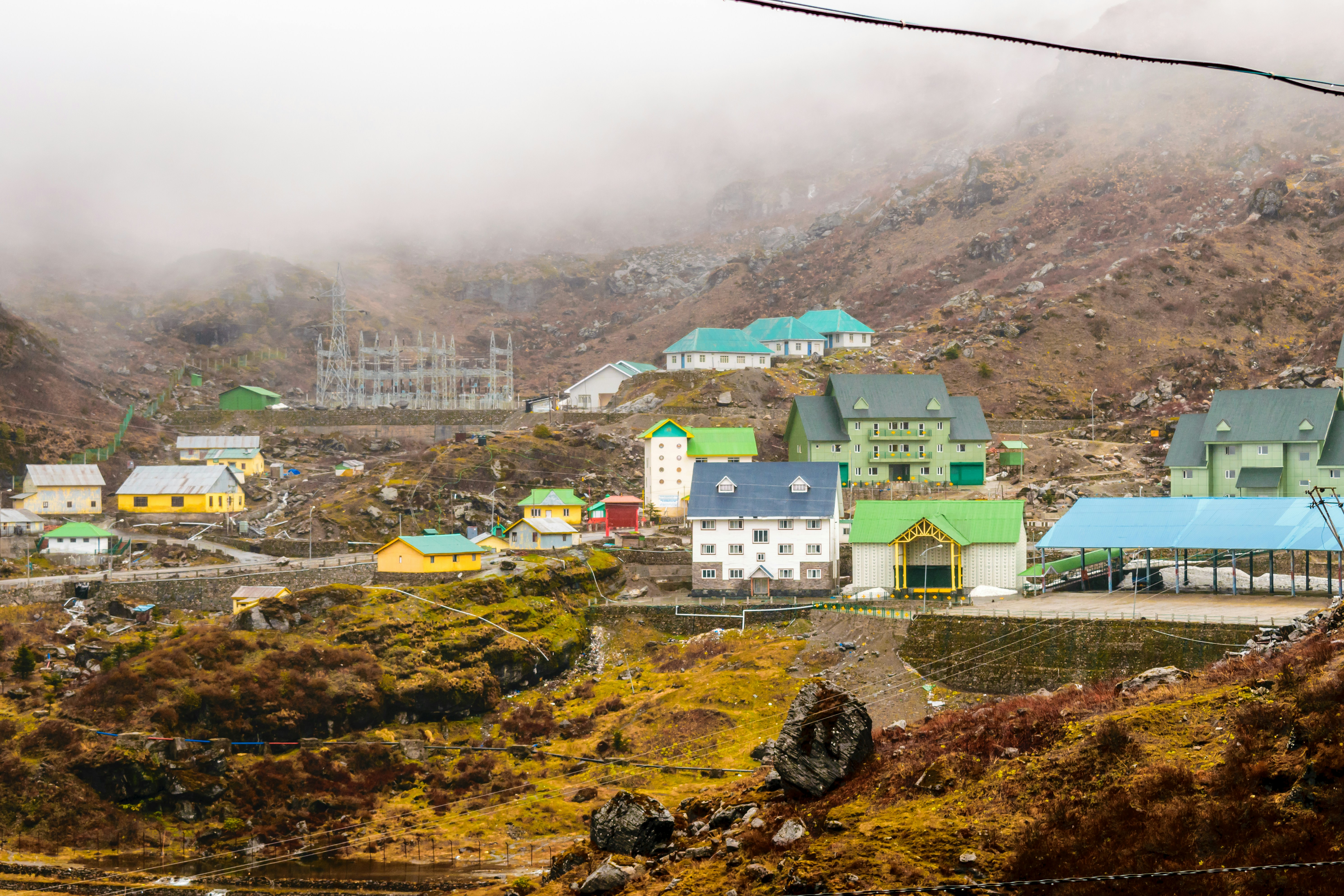 Neon-roofed Village Nestled in a Misty Volcanic Landscape