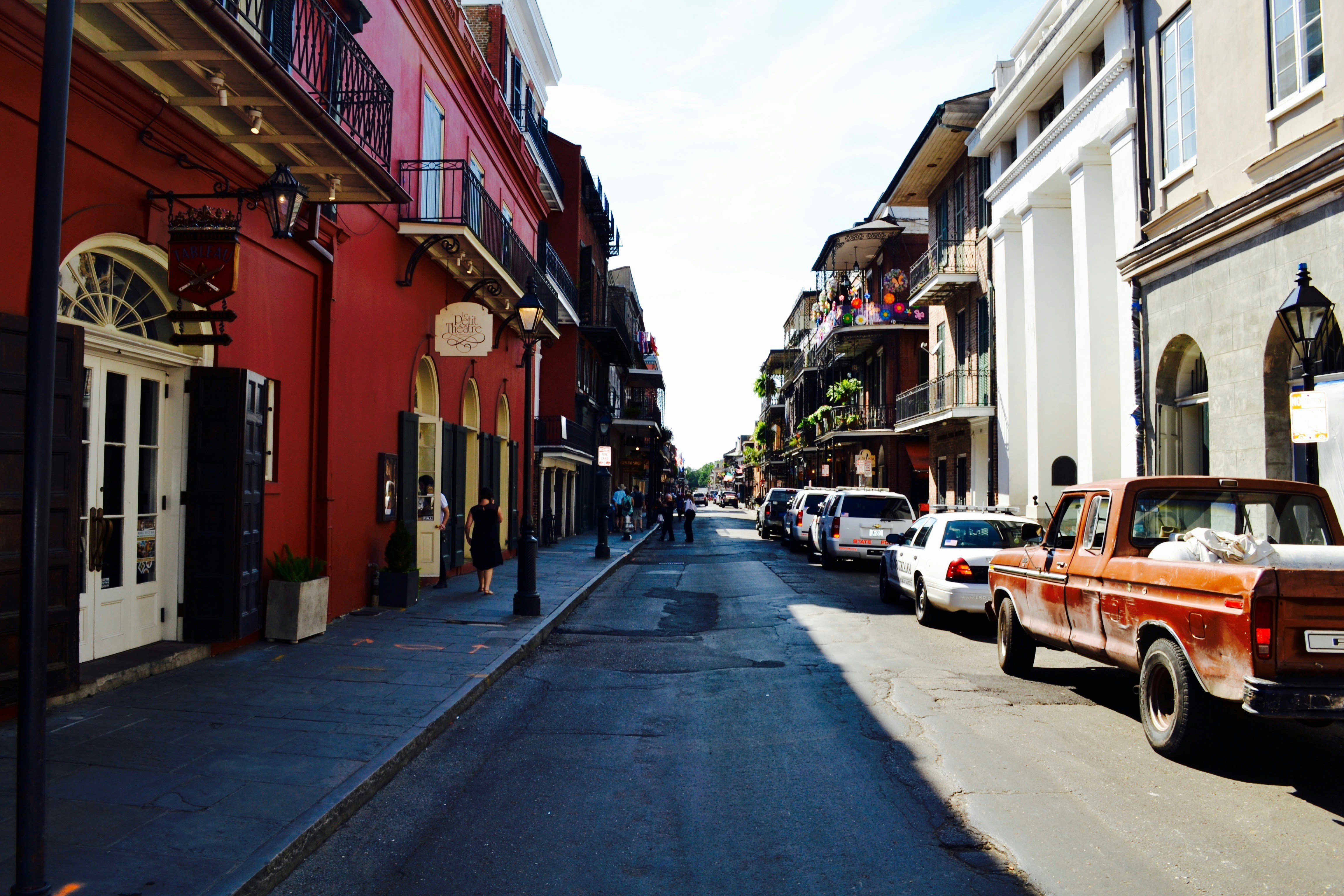 Colorful buildings and parked vehicles line a bustling street under a clear sky.