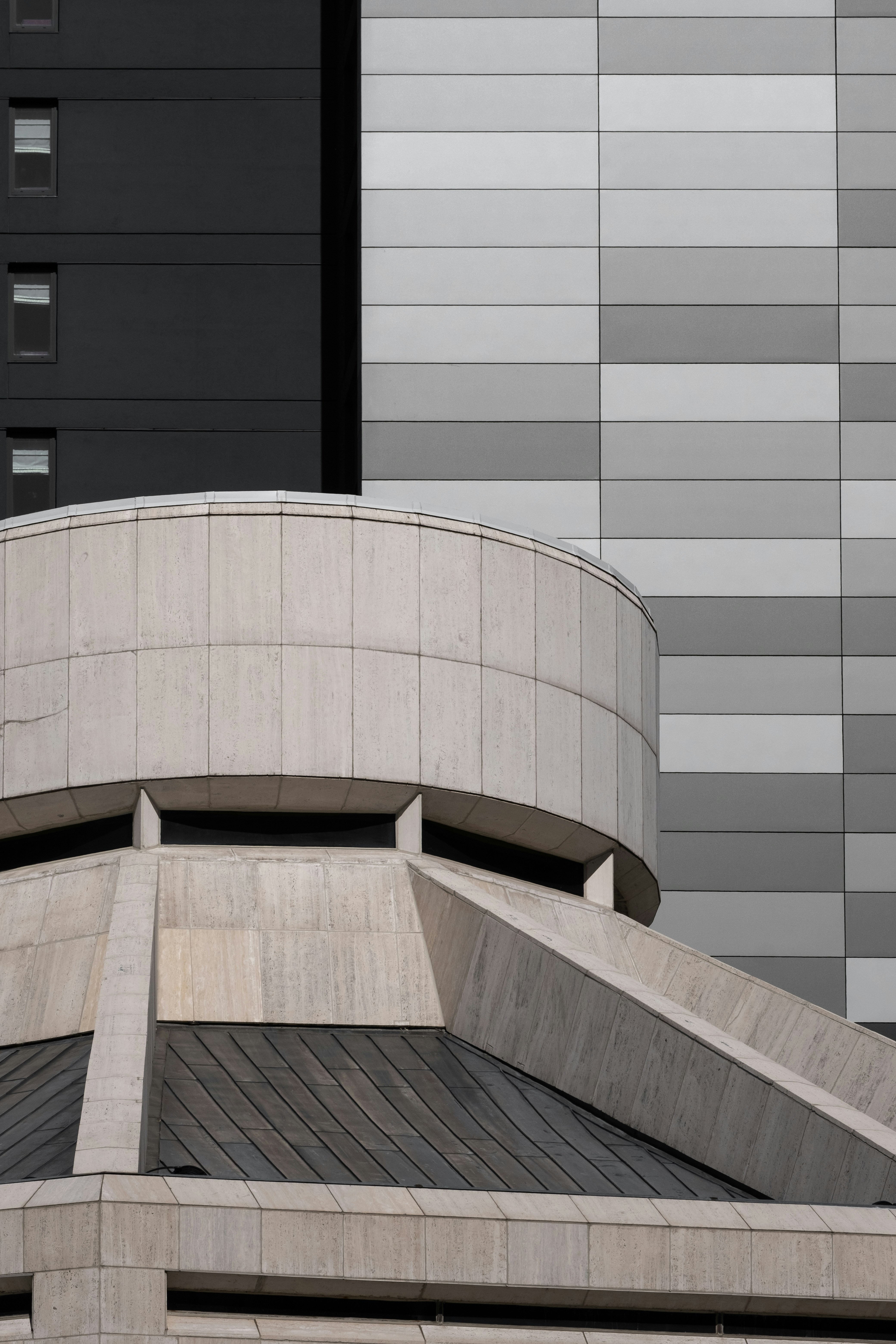 Concrete architectural feature contrasting with a modern, patterned facade. The interplay of shapes and materials showcases contemporary design.