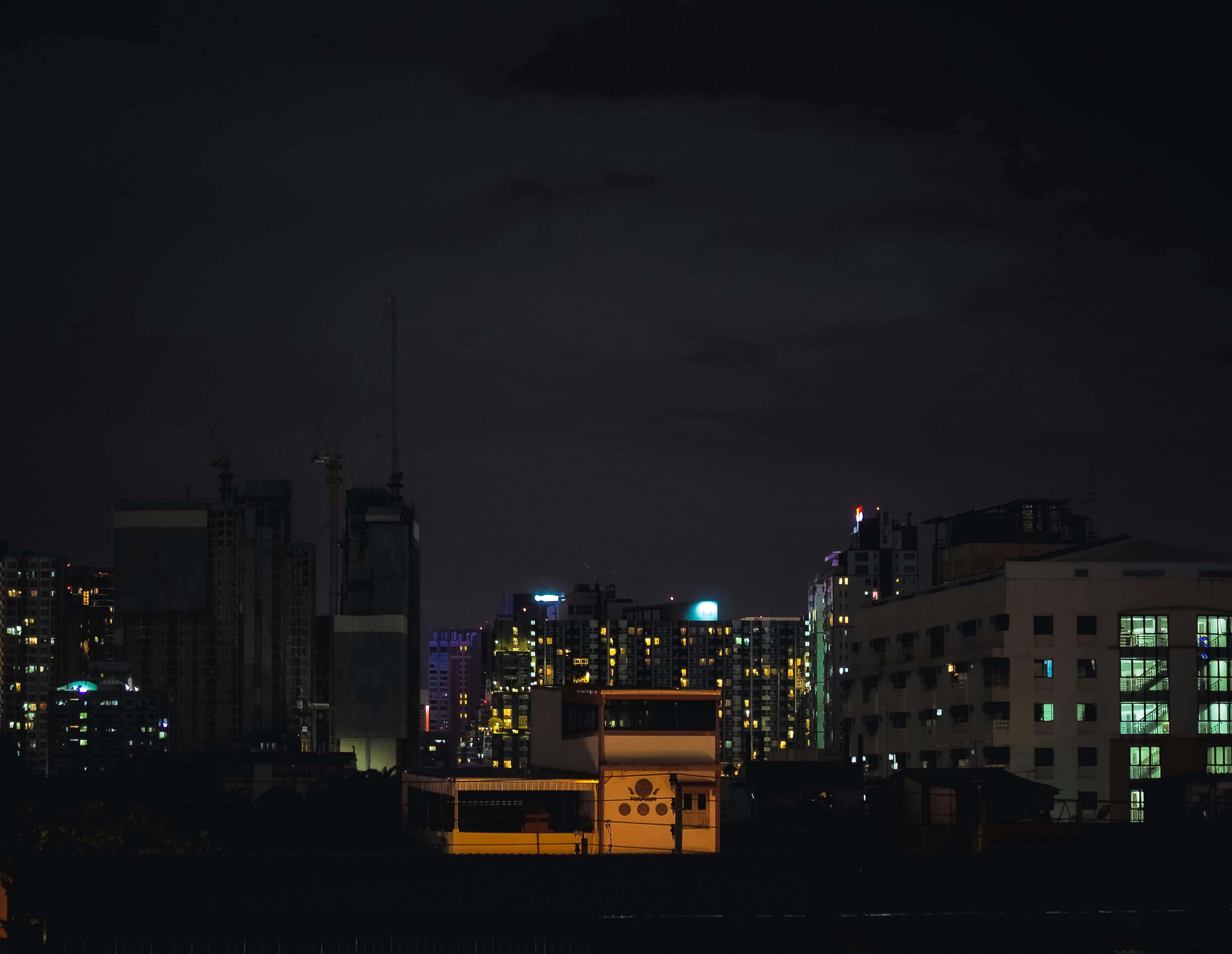 A vibrant city skyline illuminated at night, showcasing a mix of modern buildings and urban architecture against a dark sky.