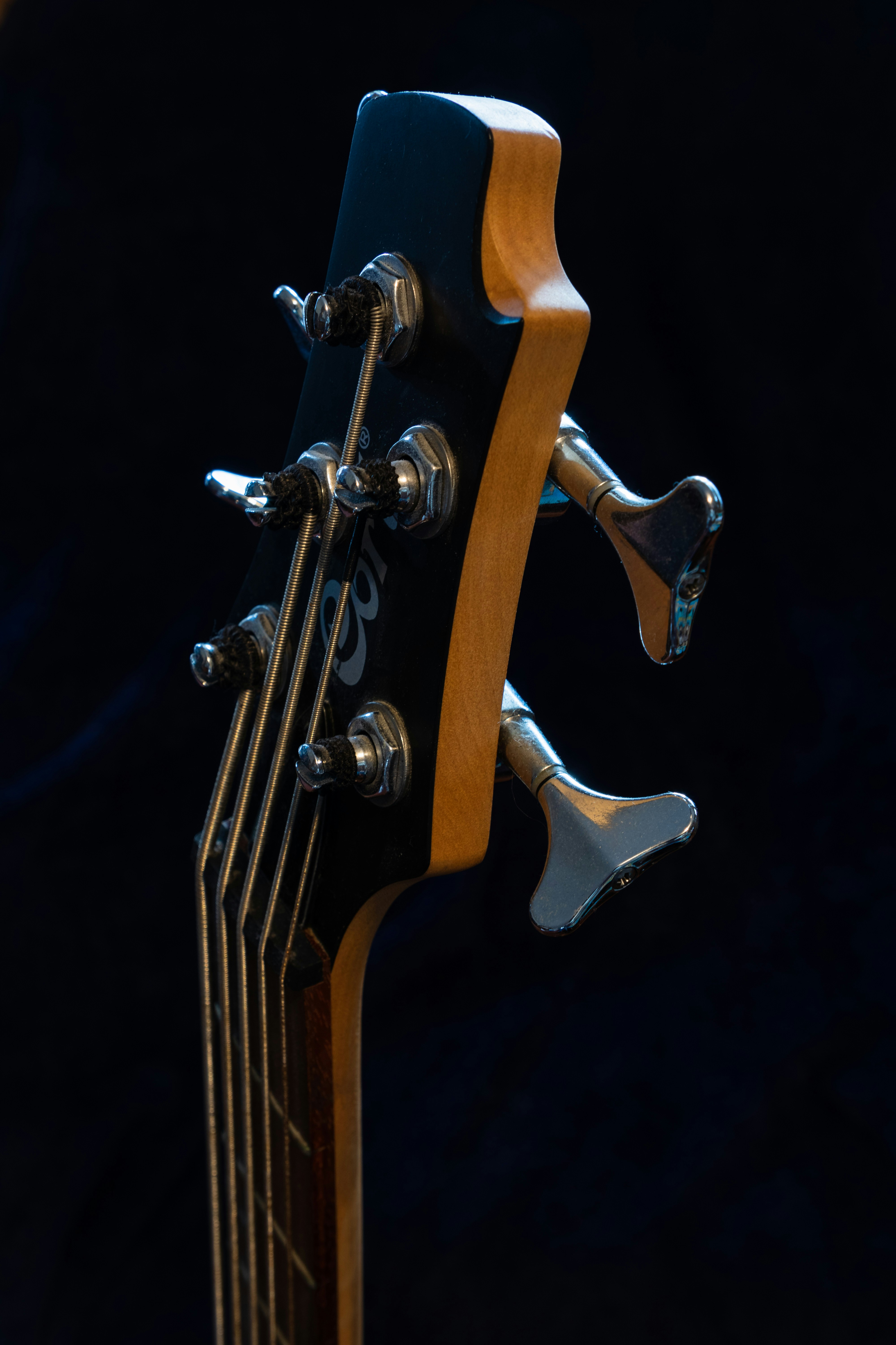 Detailed view of a guitar headstock showcasing tuning pegs and strings against a dark background.