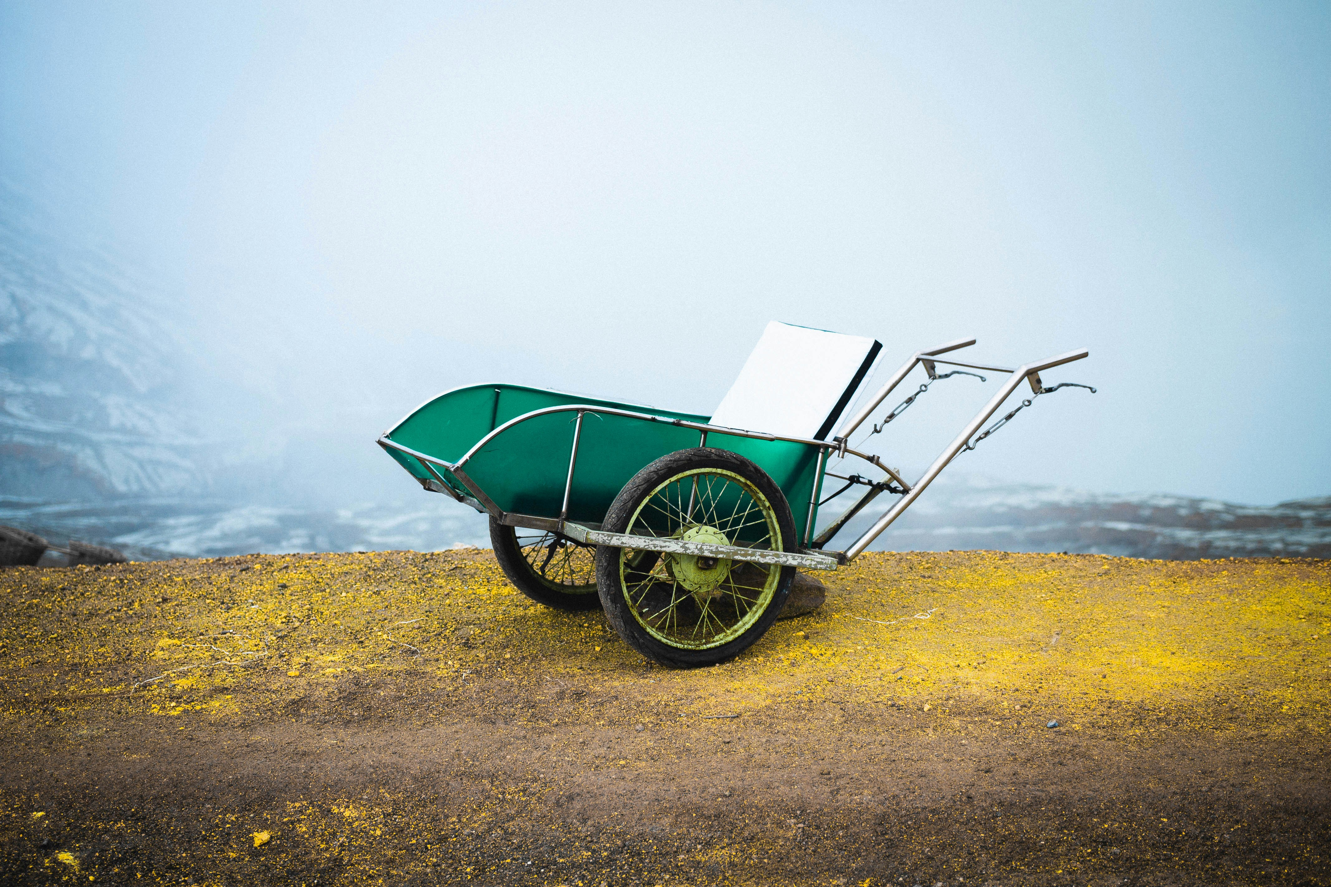 Green Wheelbarrow Resting on a Misty Riverside Path