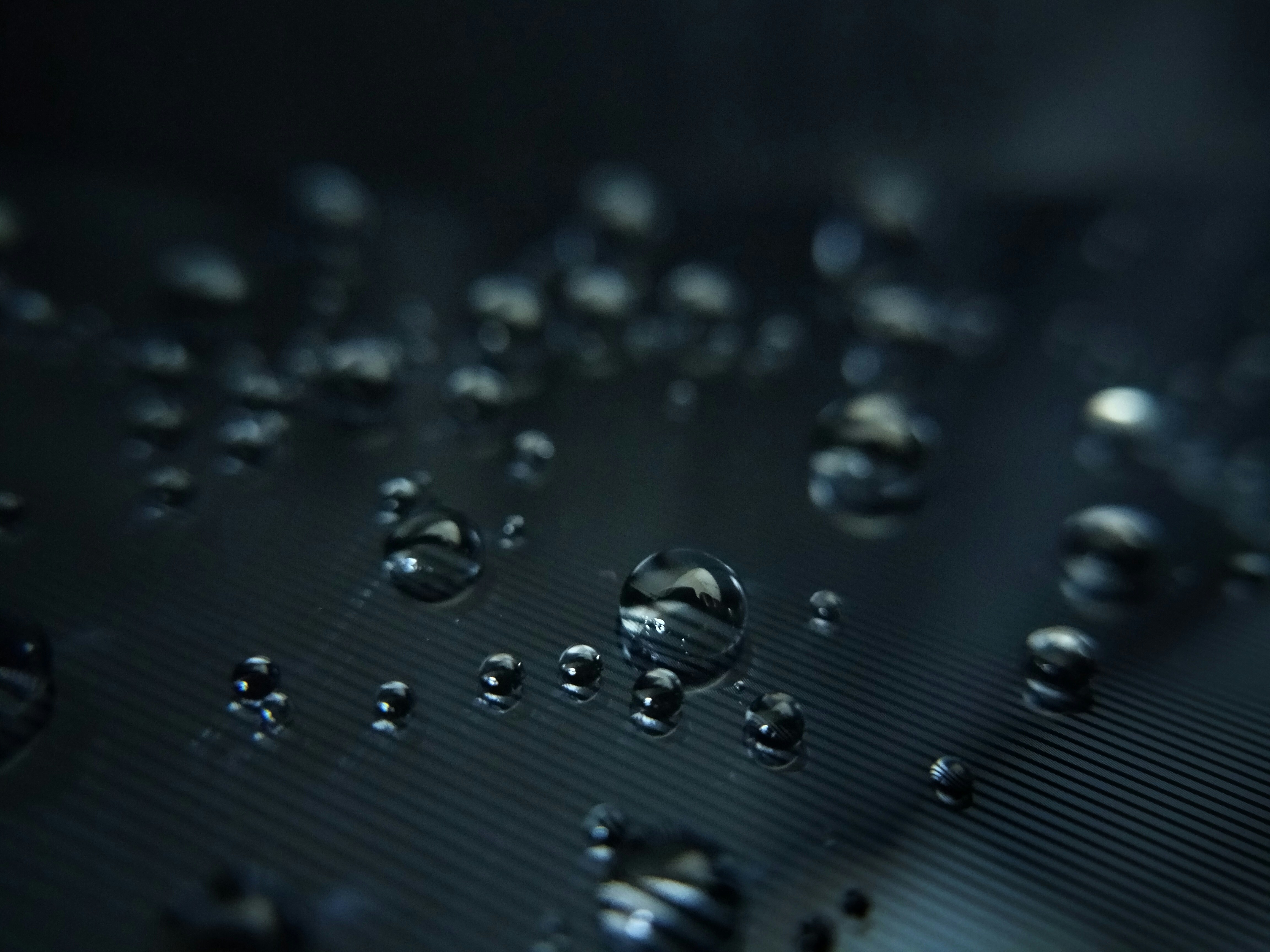 Macro shot of water droplets on a textured surface, showcasing intricate reflections and a play of light.
