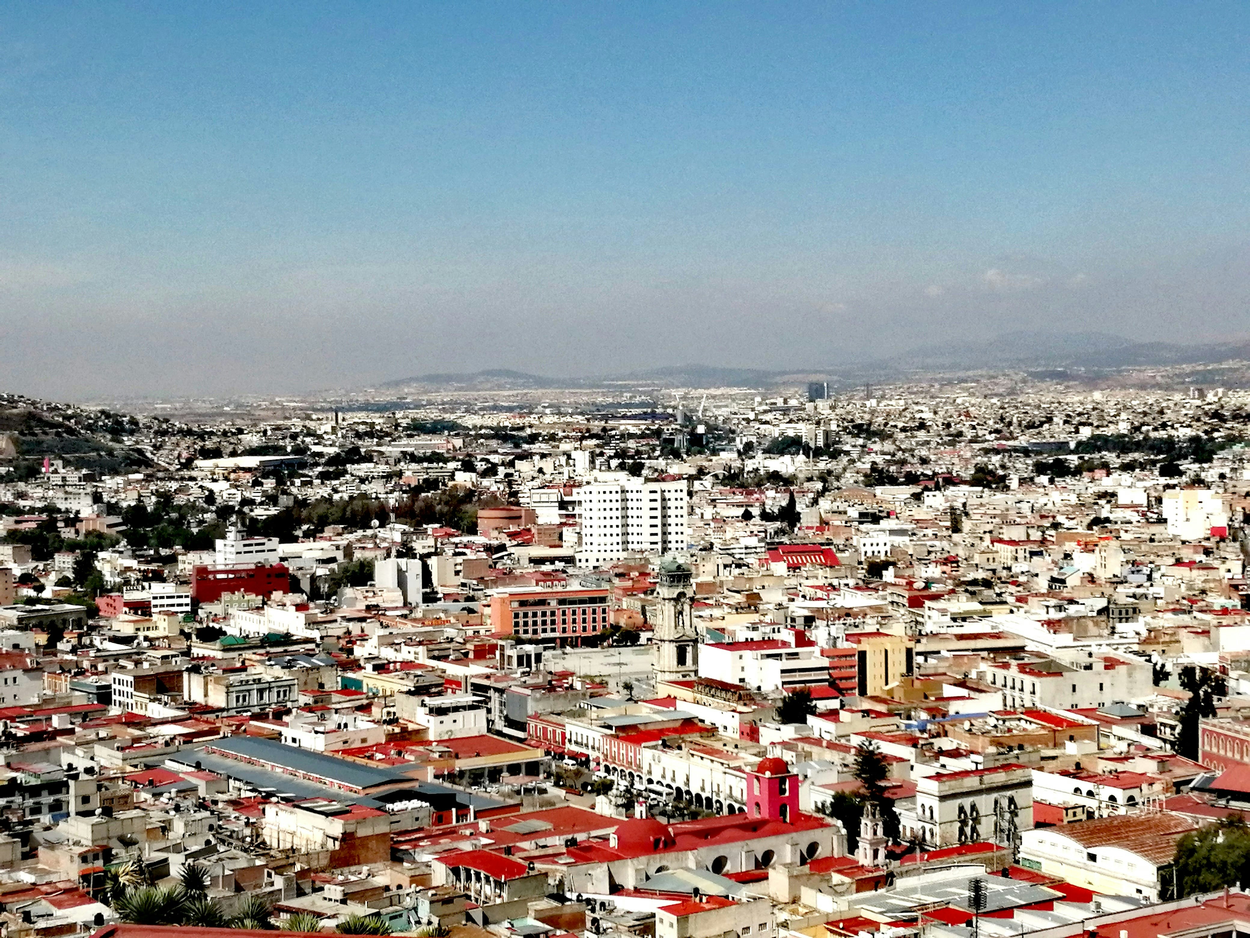 Expansive view of Pachuca's cityscape under a clear blue sky, highlighting a mix of modern and traditional architecture.