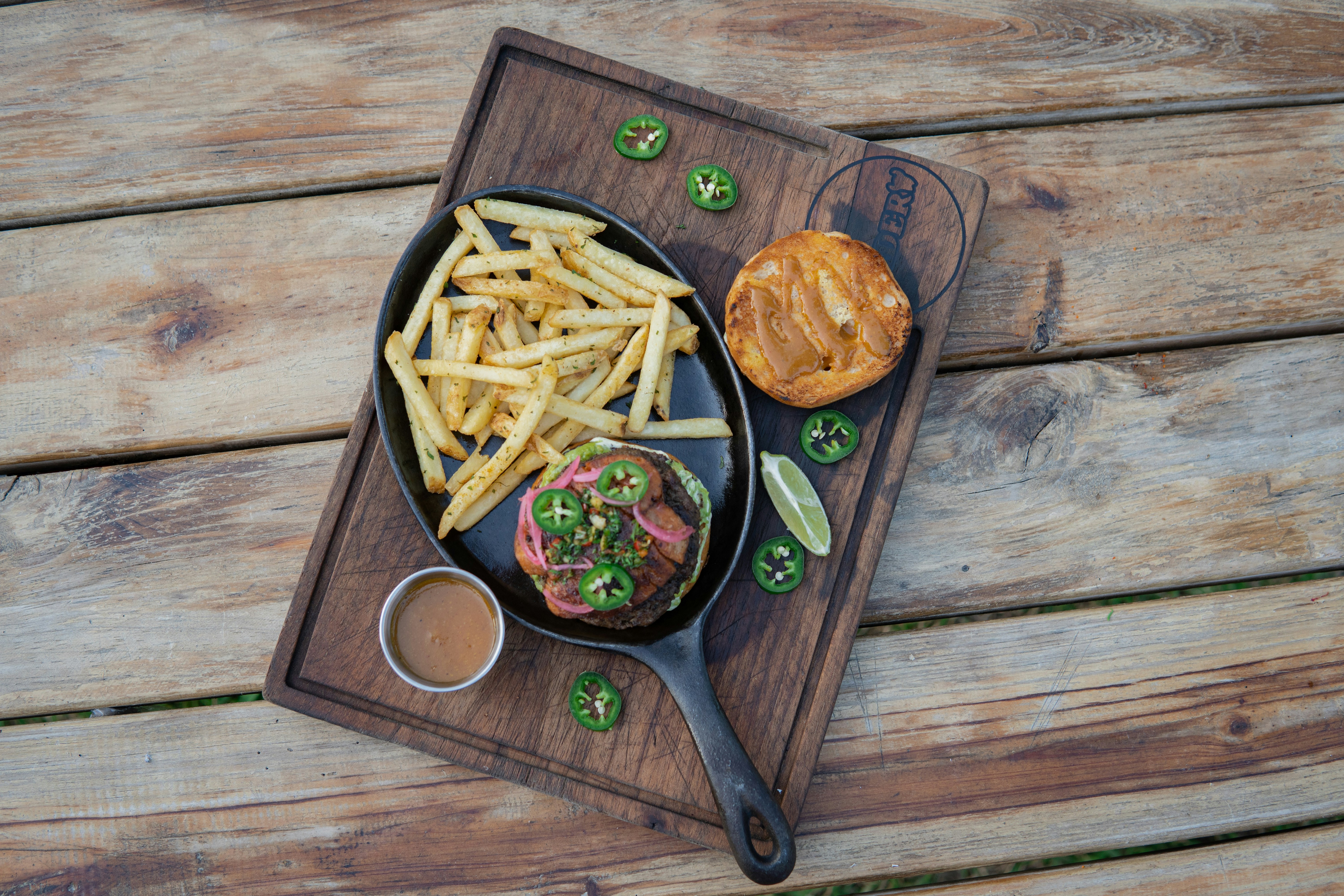 Rustic Skillet Feast on Weathered Wood: Crispy Fries and Herb-Crusted Burger