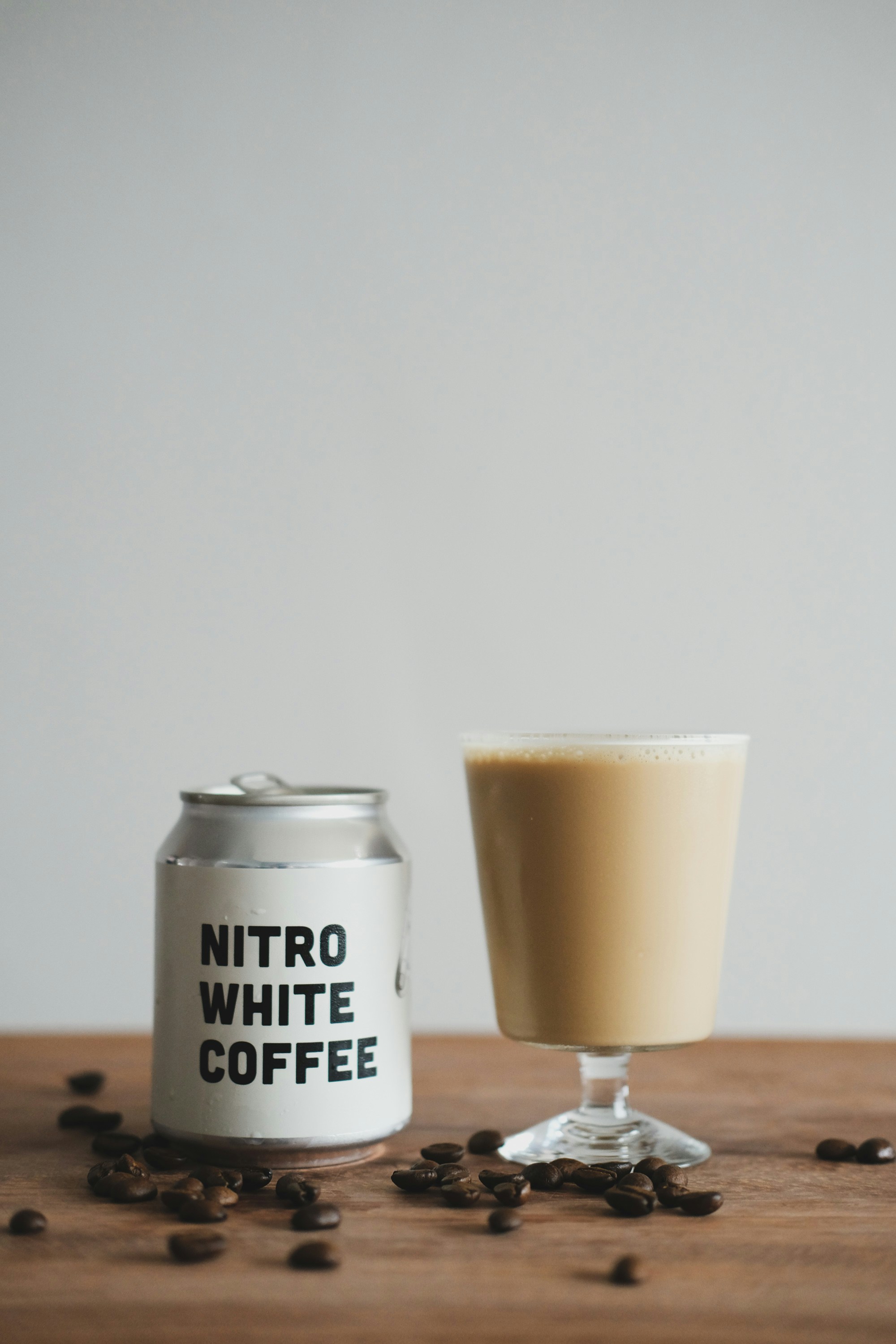 Close up shot of Pushers Nitro White Coffee, a cafe latte / flat white in a can, poured up in a stemmed glass.