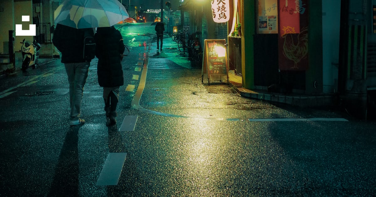 검은 재킷과 검은 바지를 입은 사람이 우산을 들고 밤 시간 동안 보도를 걷고 있다 사진 Unsplash의 무료 술집 이미지