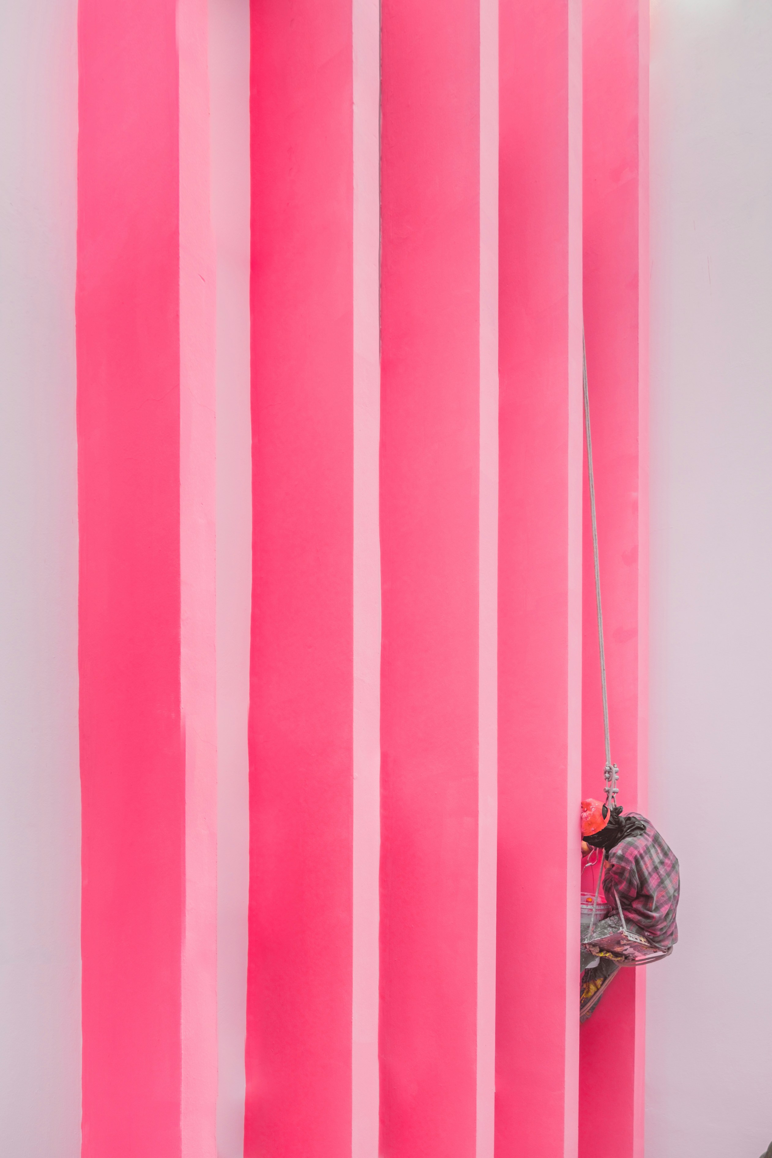 Pink Columned Facade with Climber Suspended by Wires