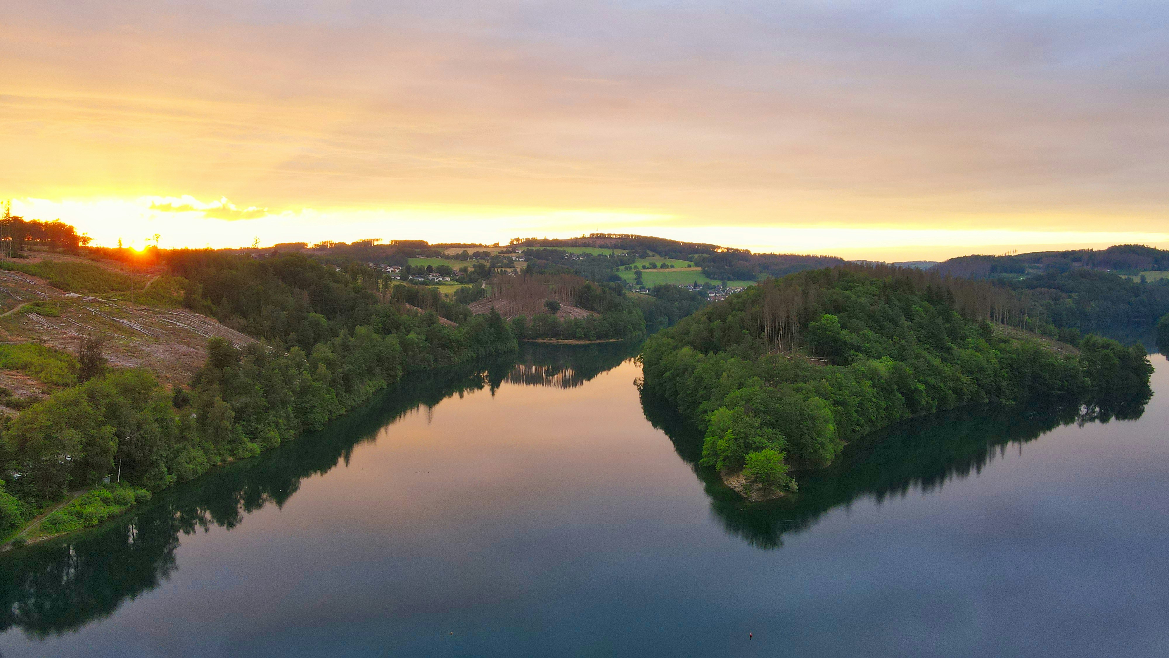River winding through lush hills under a vibrant sunrise sky.