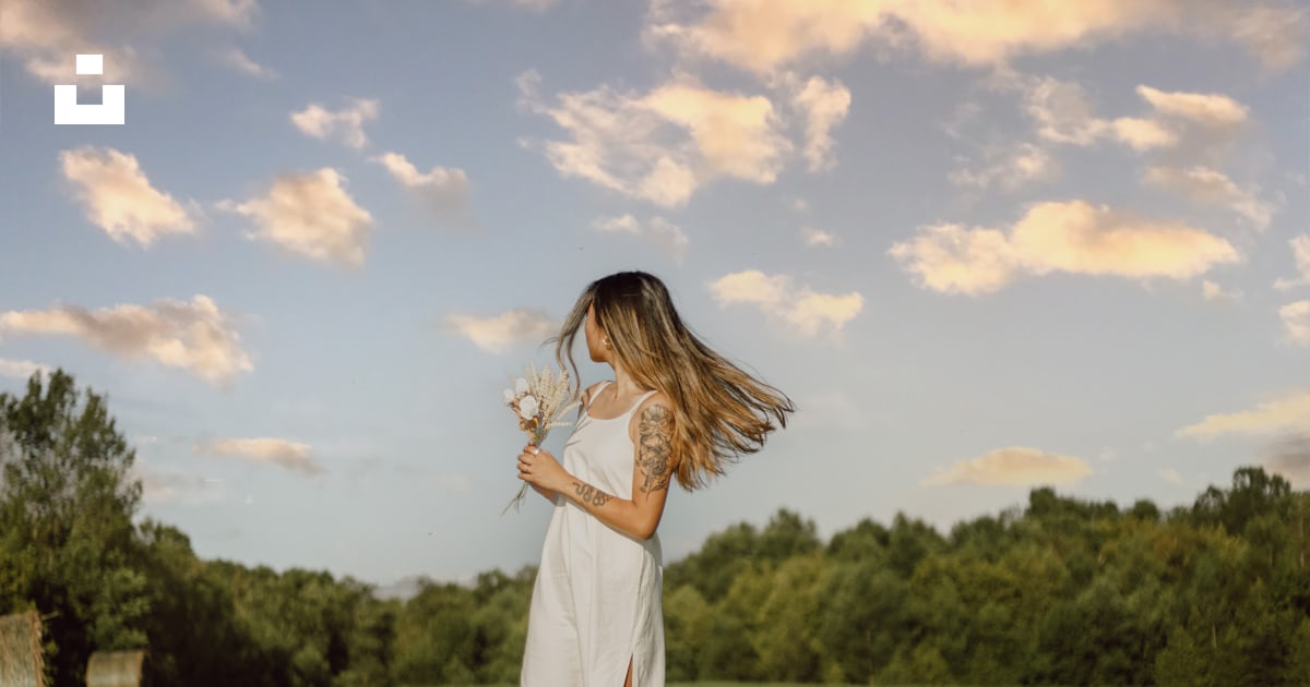 青と白の曇り空の下、緑の草原に立つ白いドレスを着た女性の写真 Unsplashの陸の無料画像