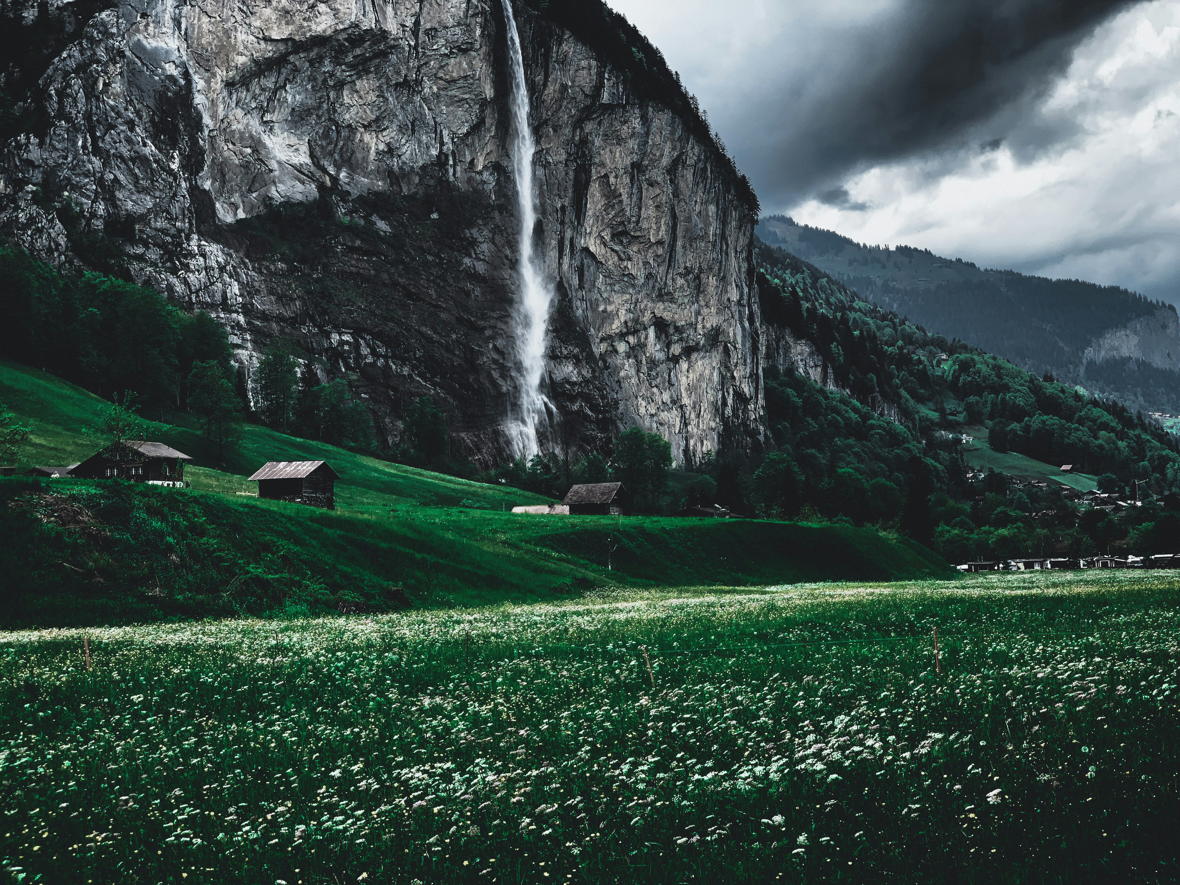 Waterfalls on green grass field near gray rocky mountain under white ...