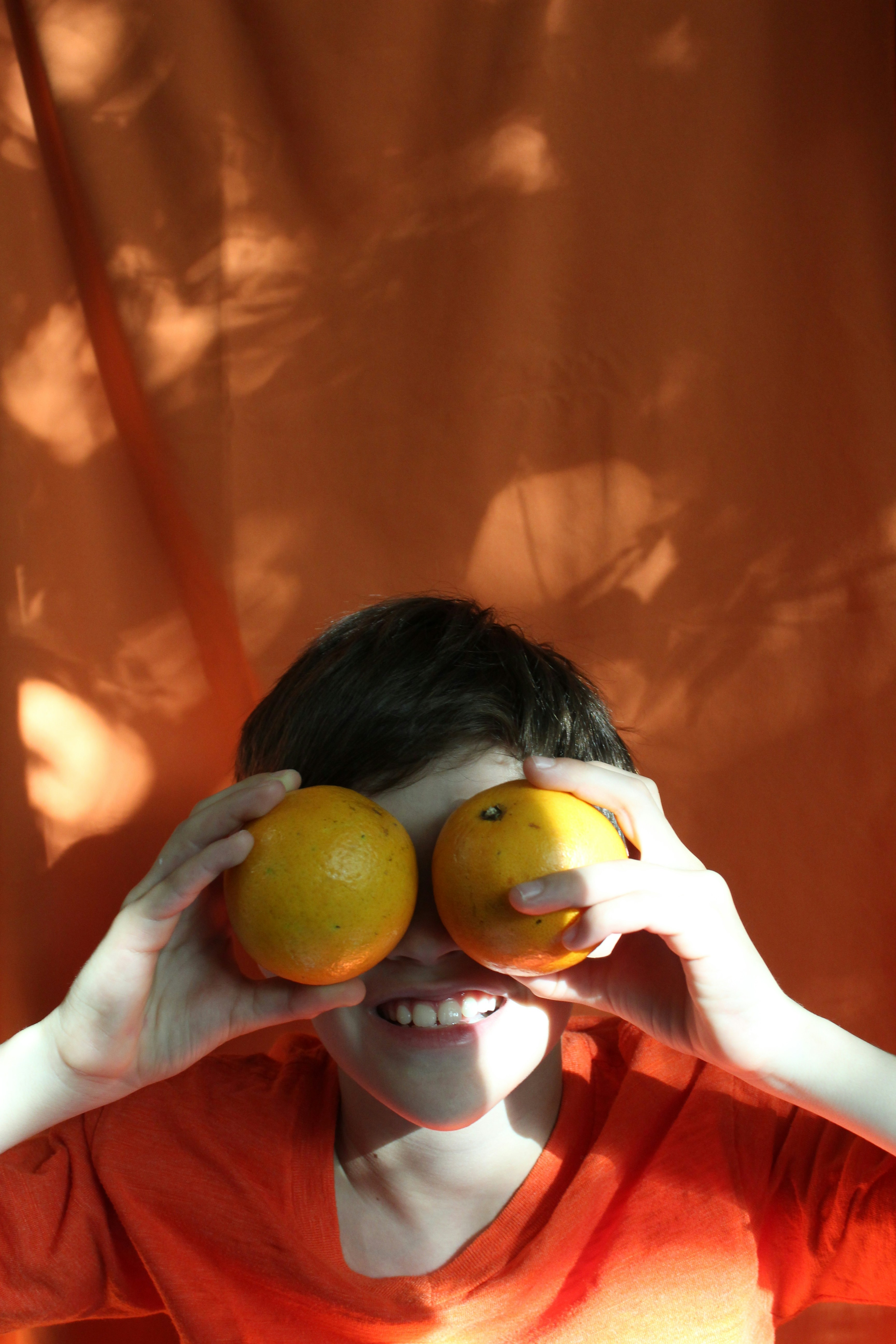 orange monochrome portrait, smiling boy with oranges in his eyes