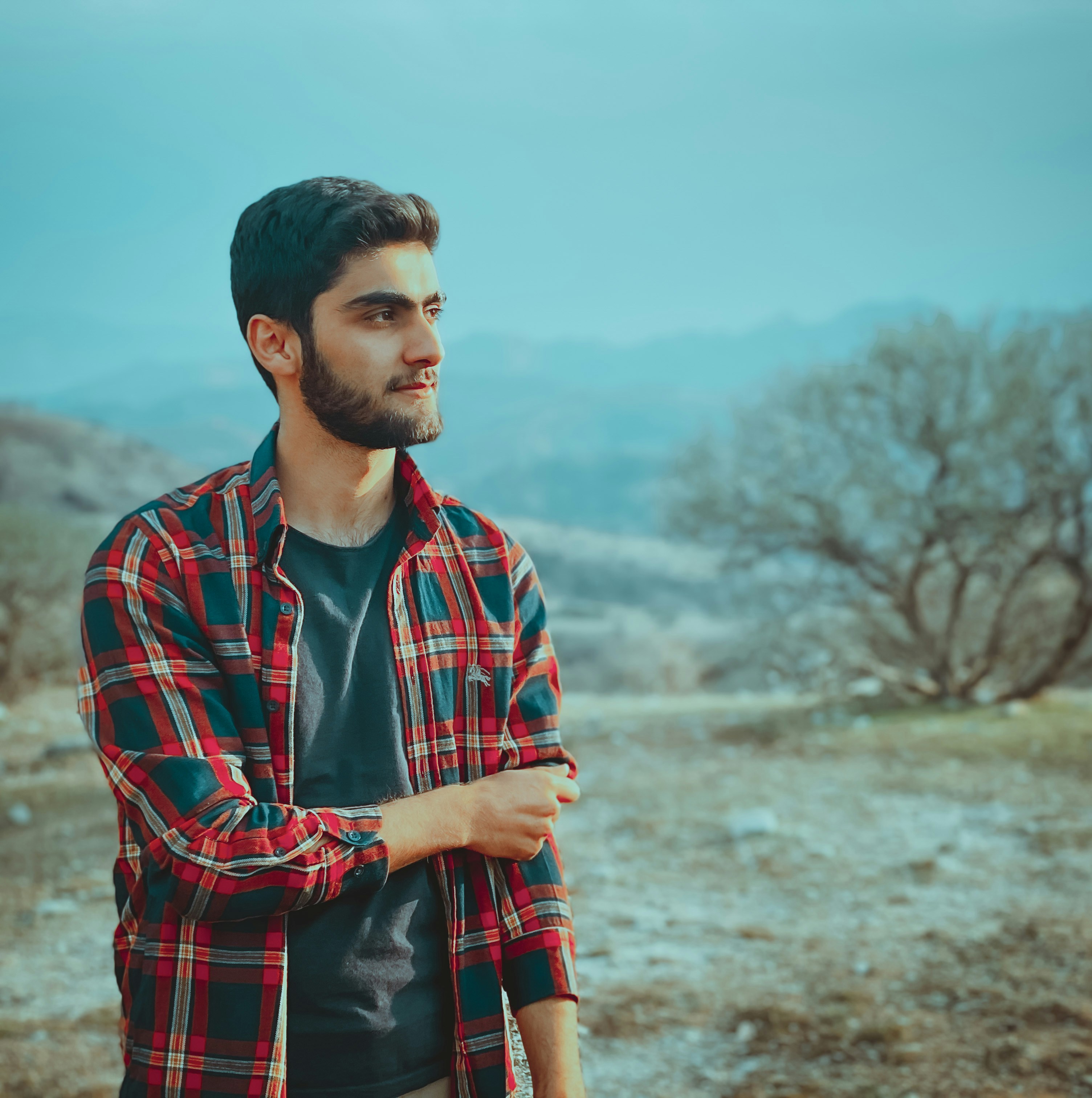 Man in red and black plaid dress shirt standing on brown field during ...