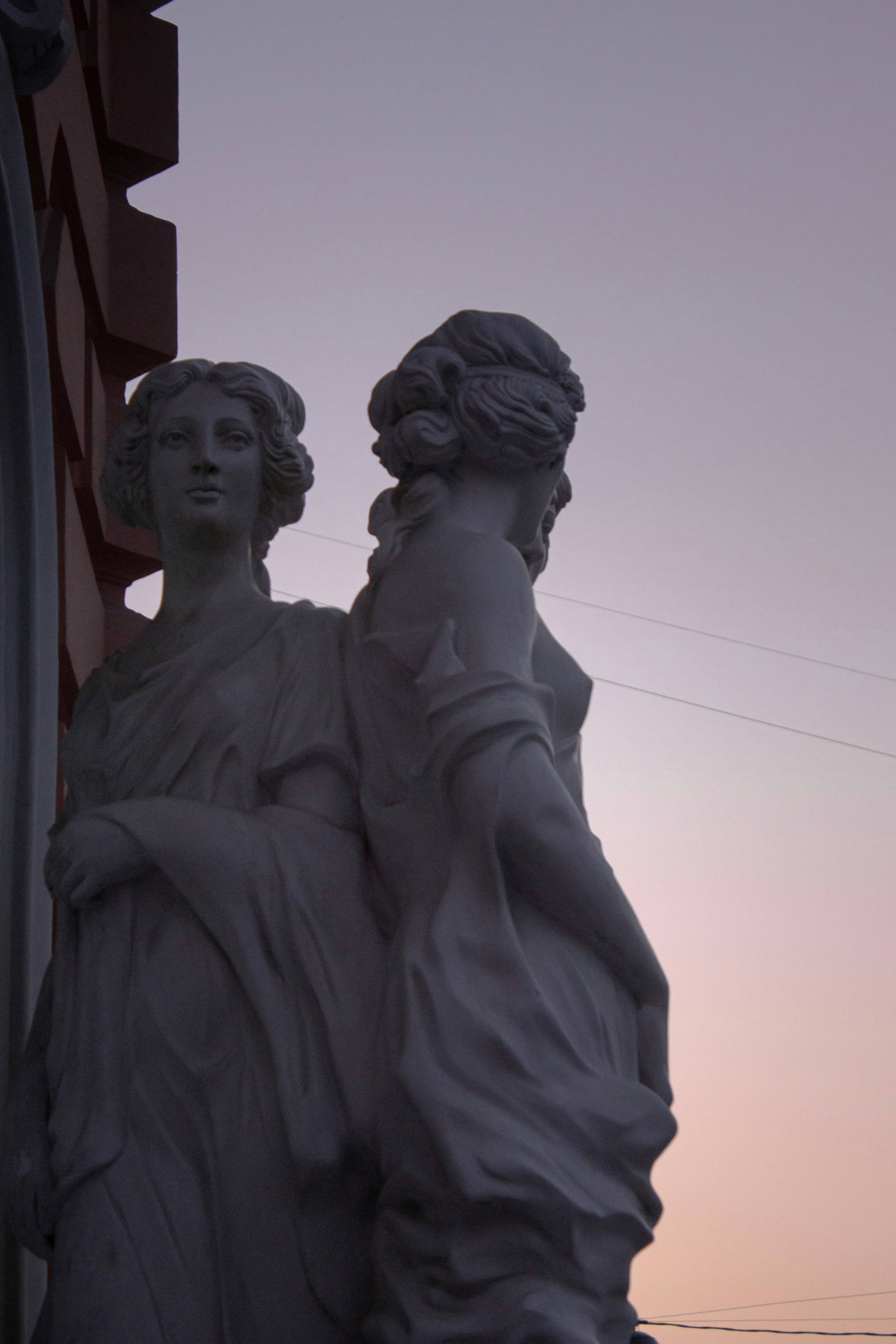 Twin Statues at Dusk: Classical Carvings Against a Purple Horizon