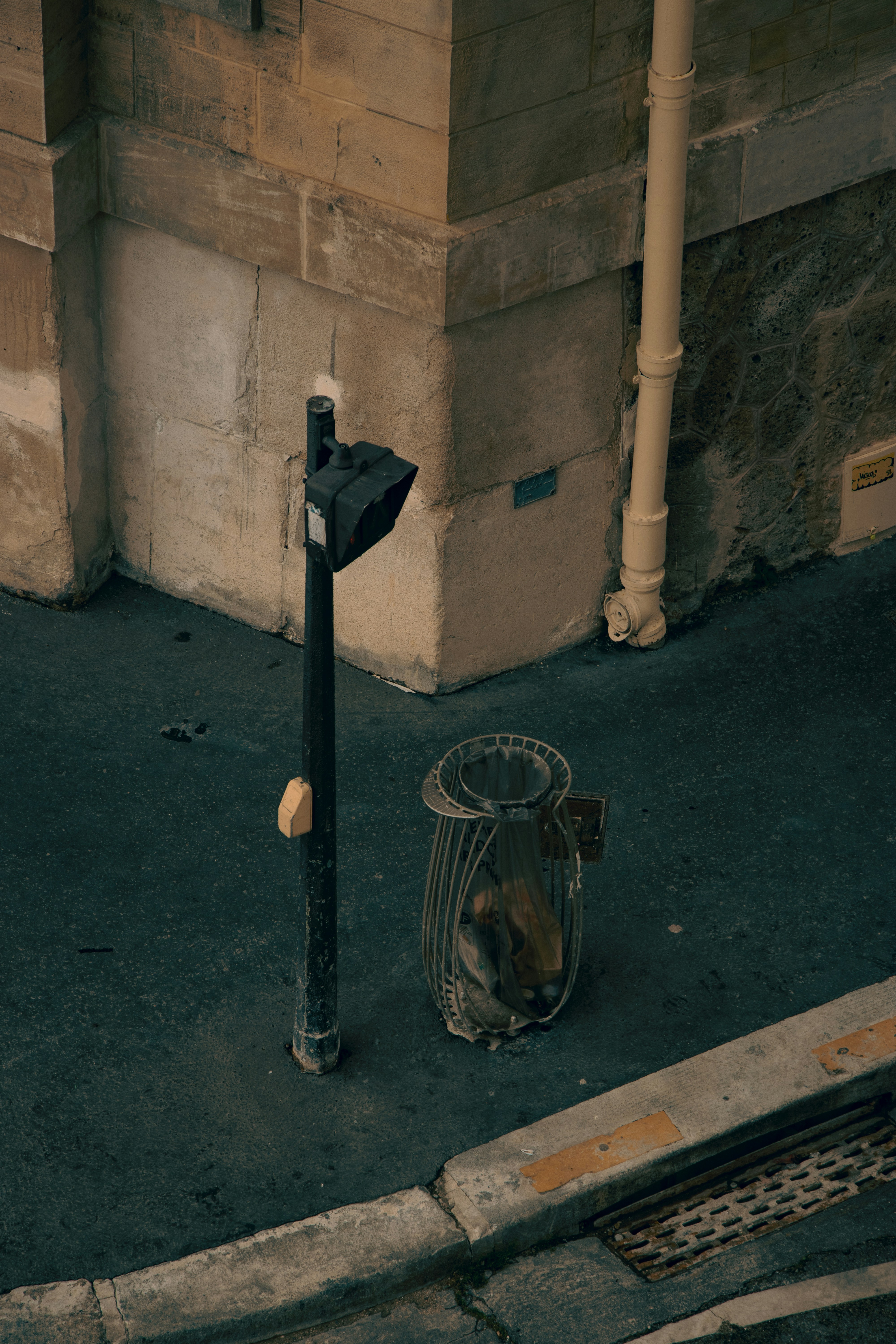 Urban Quiet: A Weathered Street Corner with a Worn Out Trash Can