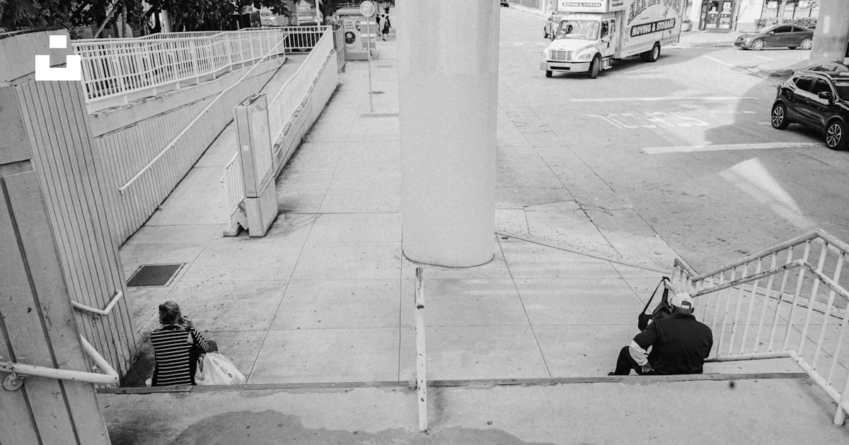 Foto Foto En Escala De Grises De Una Persona Sentada En Una Acera
