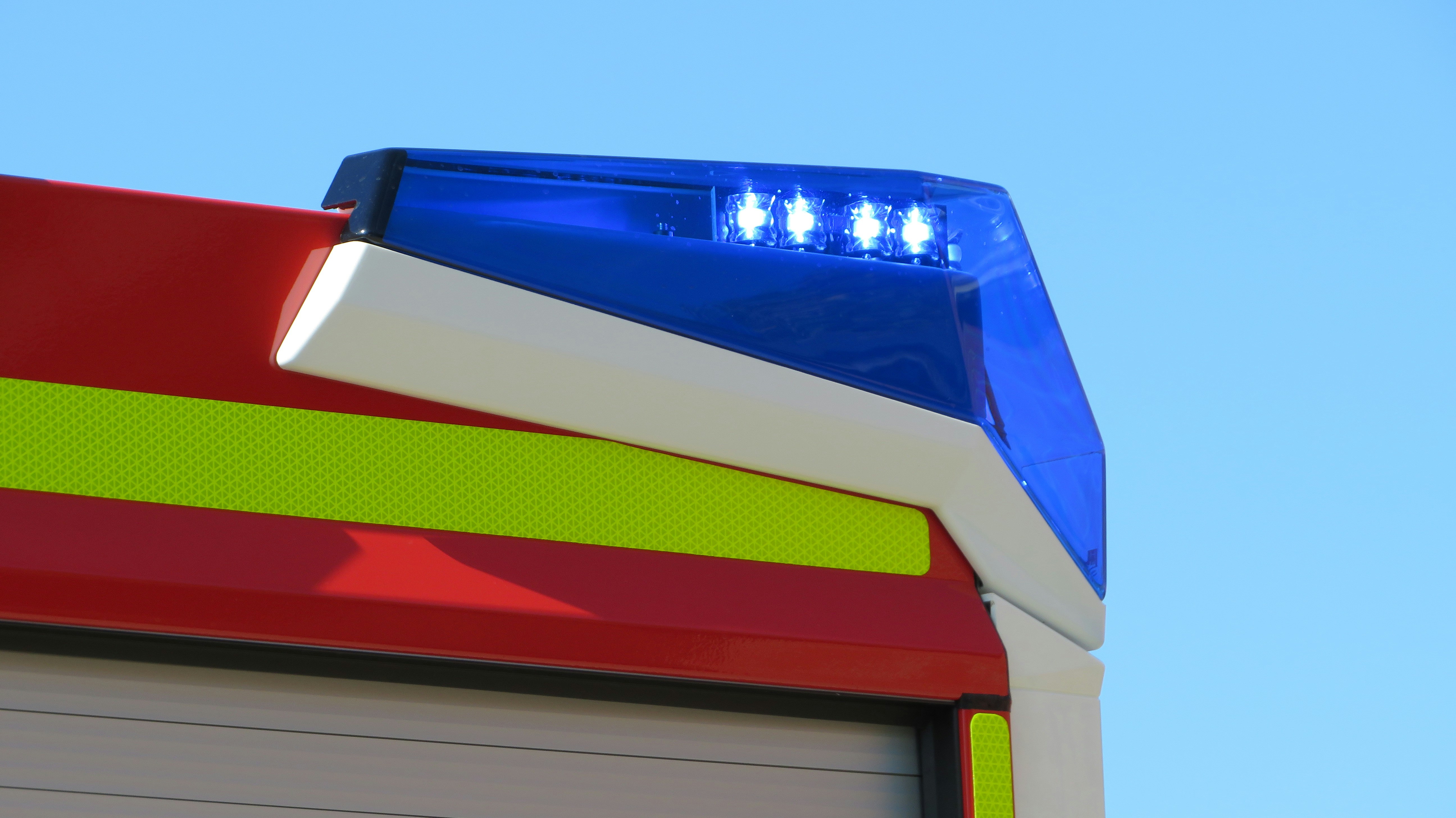 Blue beacon at the edge of a red emergency vehicle against a clear sky