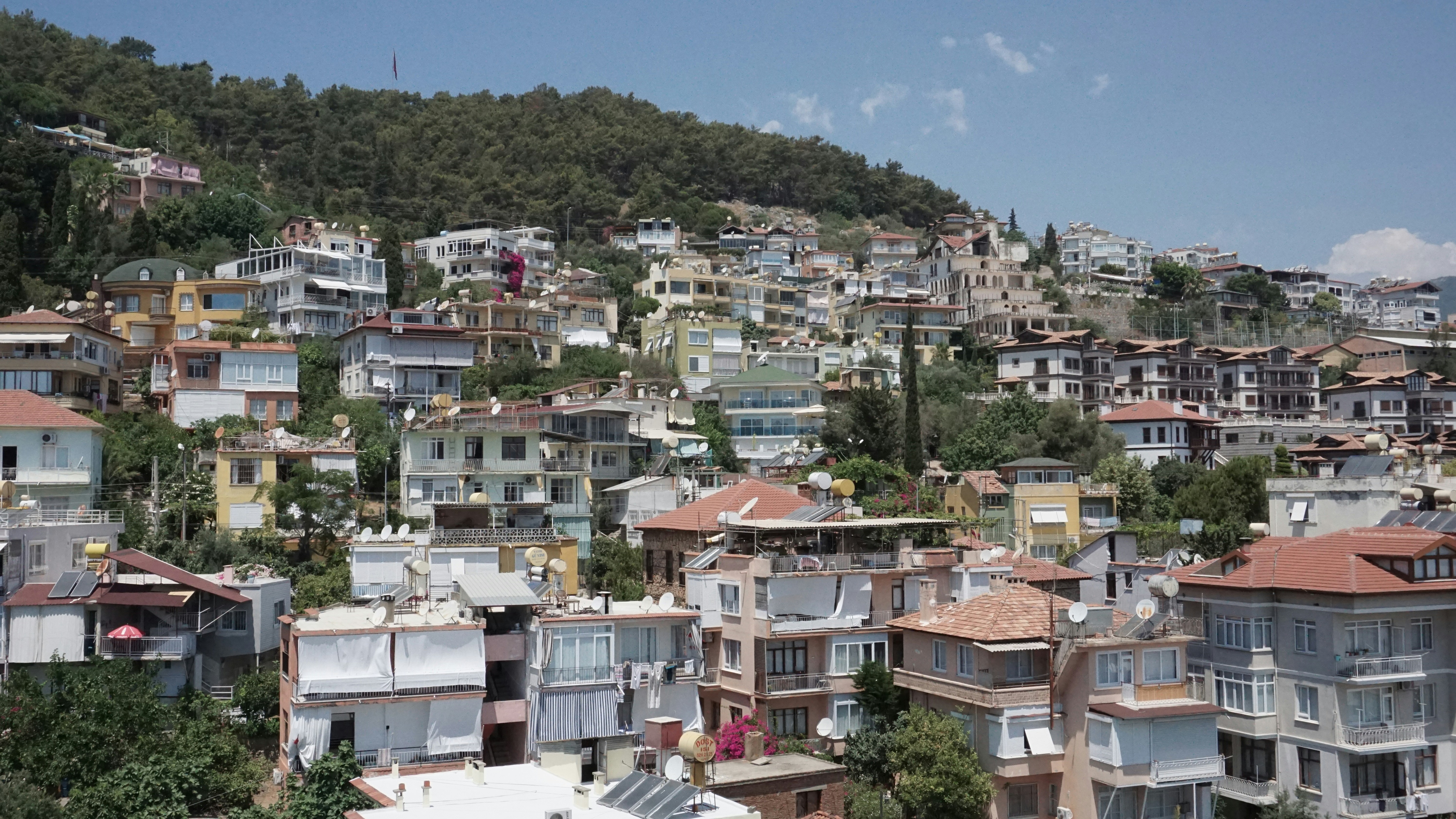 Clustered houses with red roofs on a hillside under a clear blue sky.