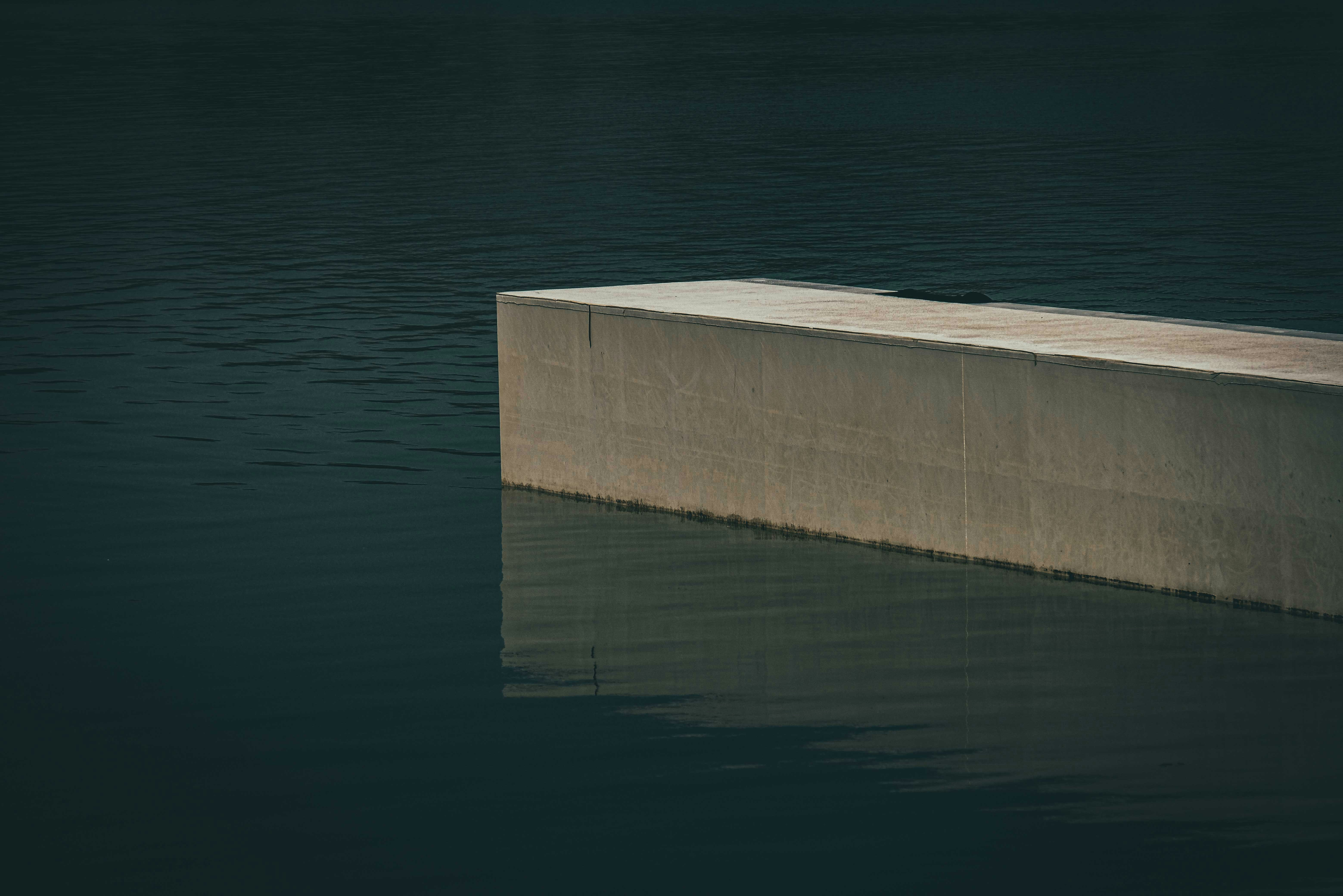 Edge of Quiet Teal: Concrete Jetty Extends into Still Water