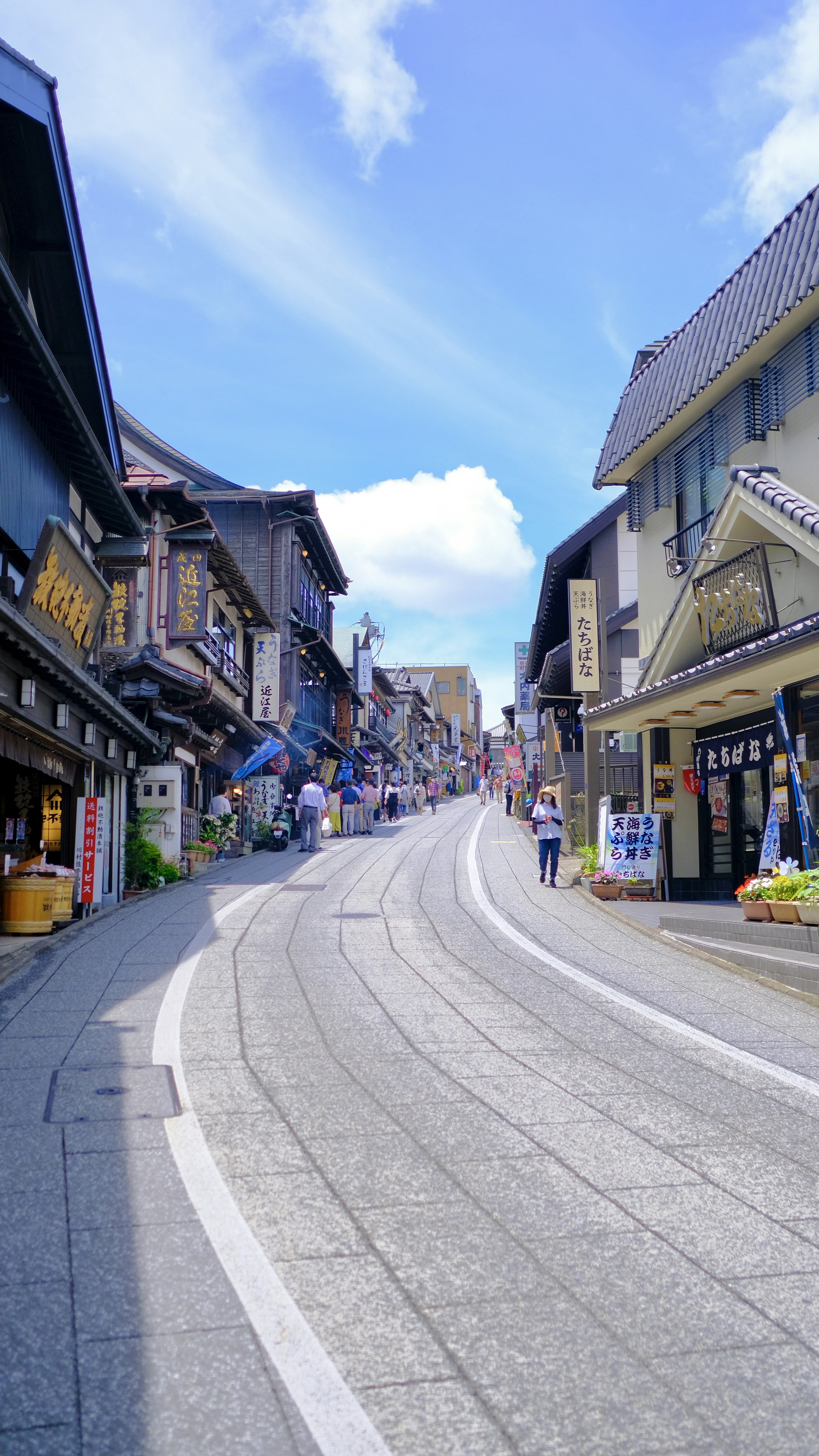 Curved street lined with traditional shops under a bright blue sky.