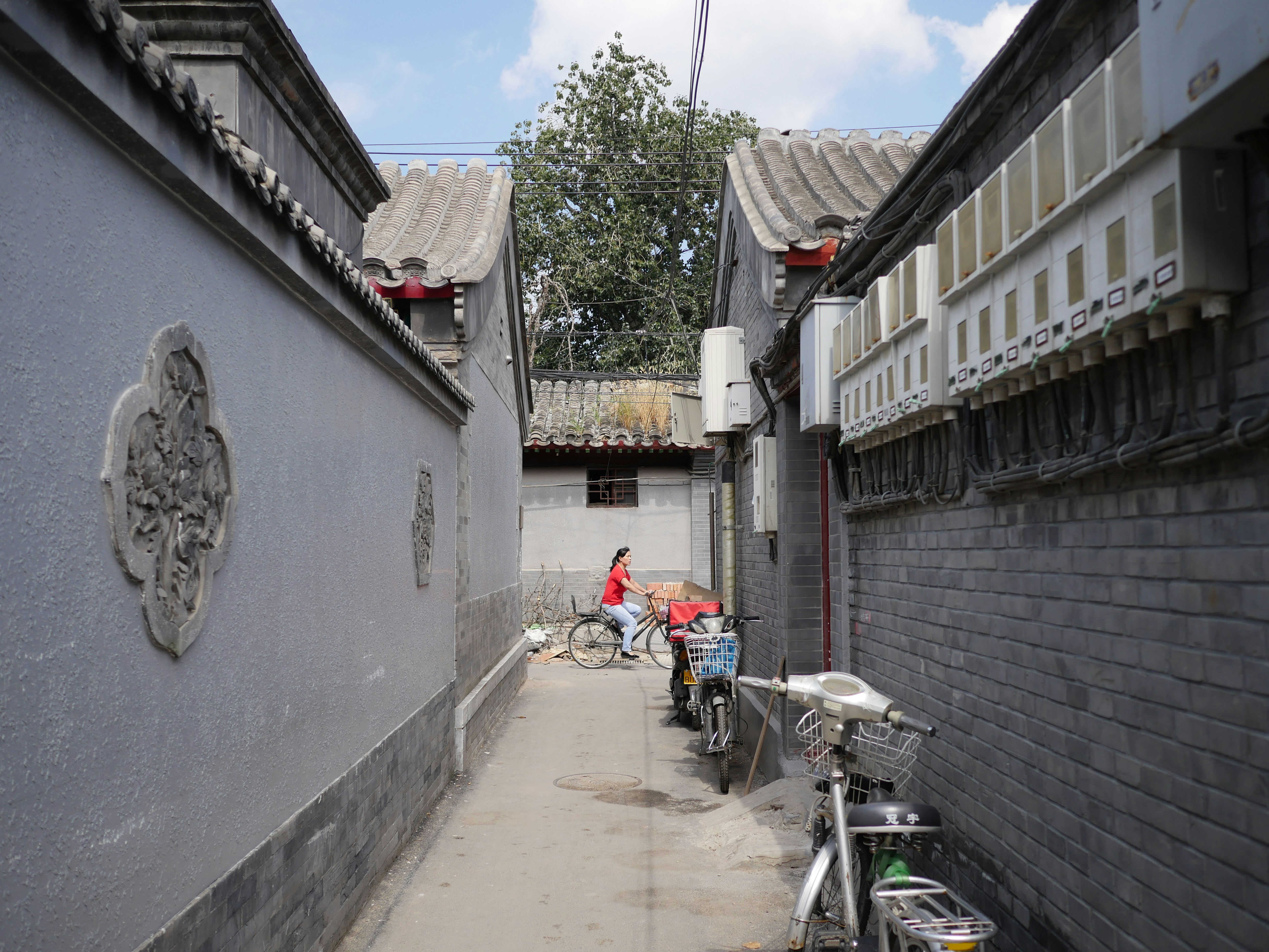 man in red shirt riding motorcycle near concrete building during daytime