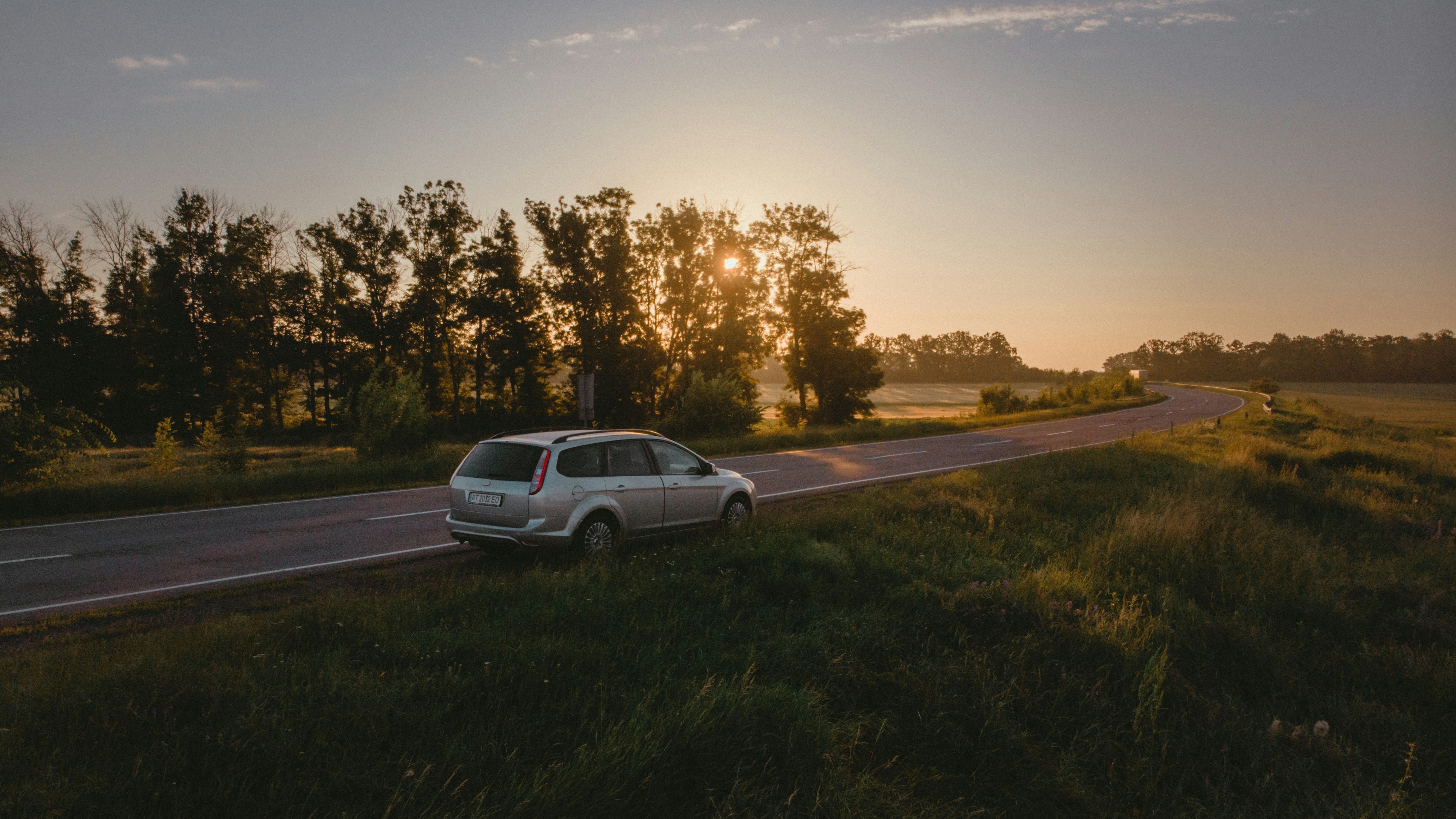 Dawn Bend: A Silver Hatchback Paused on a Sunlit Country Road