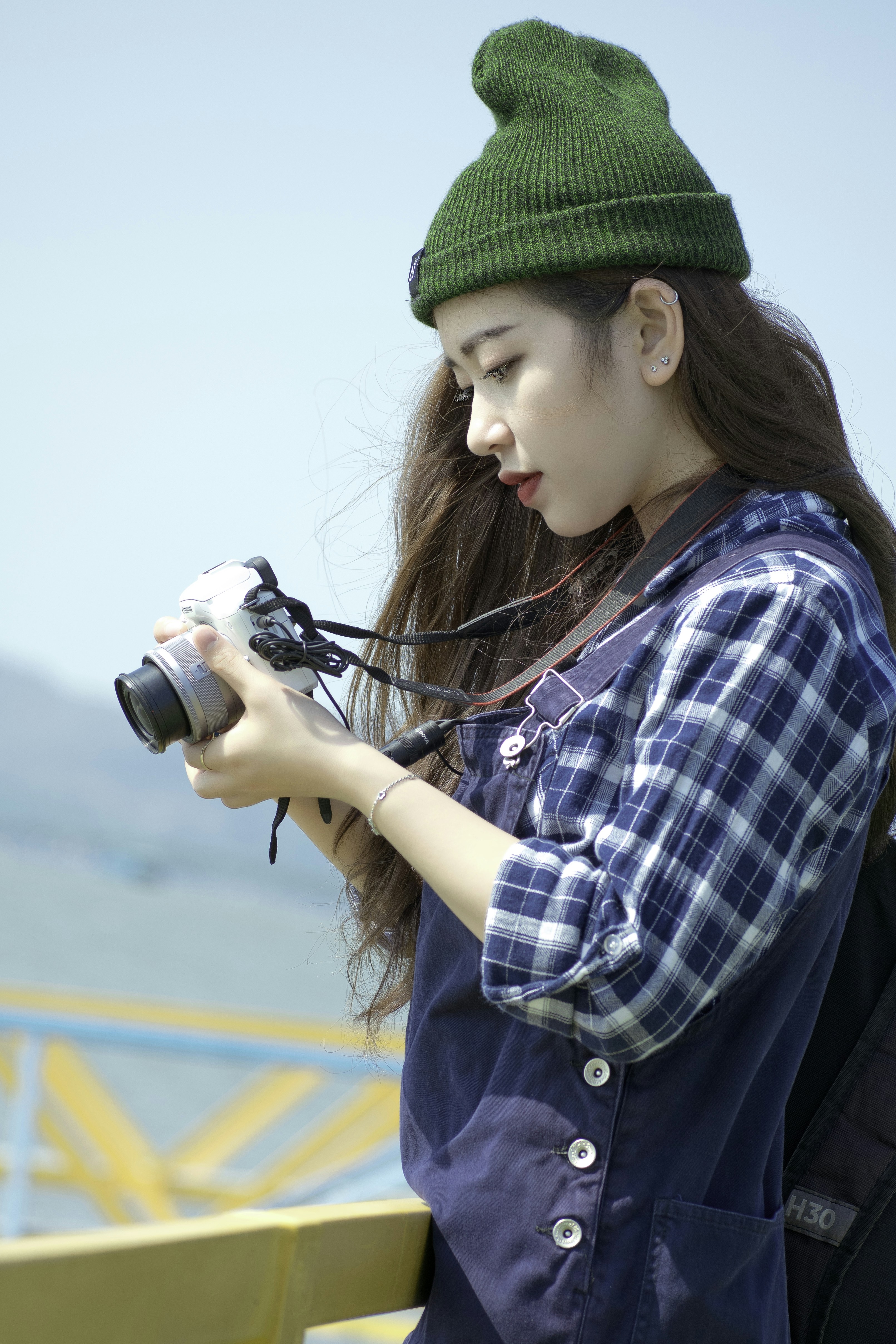 woman in blue and white plaid dress shirt holding black dslr camera