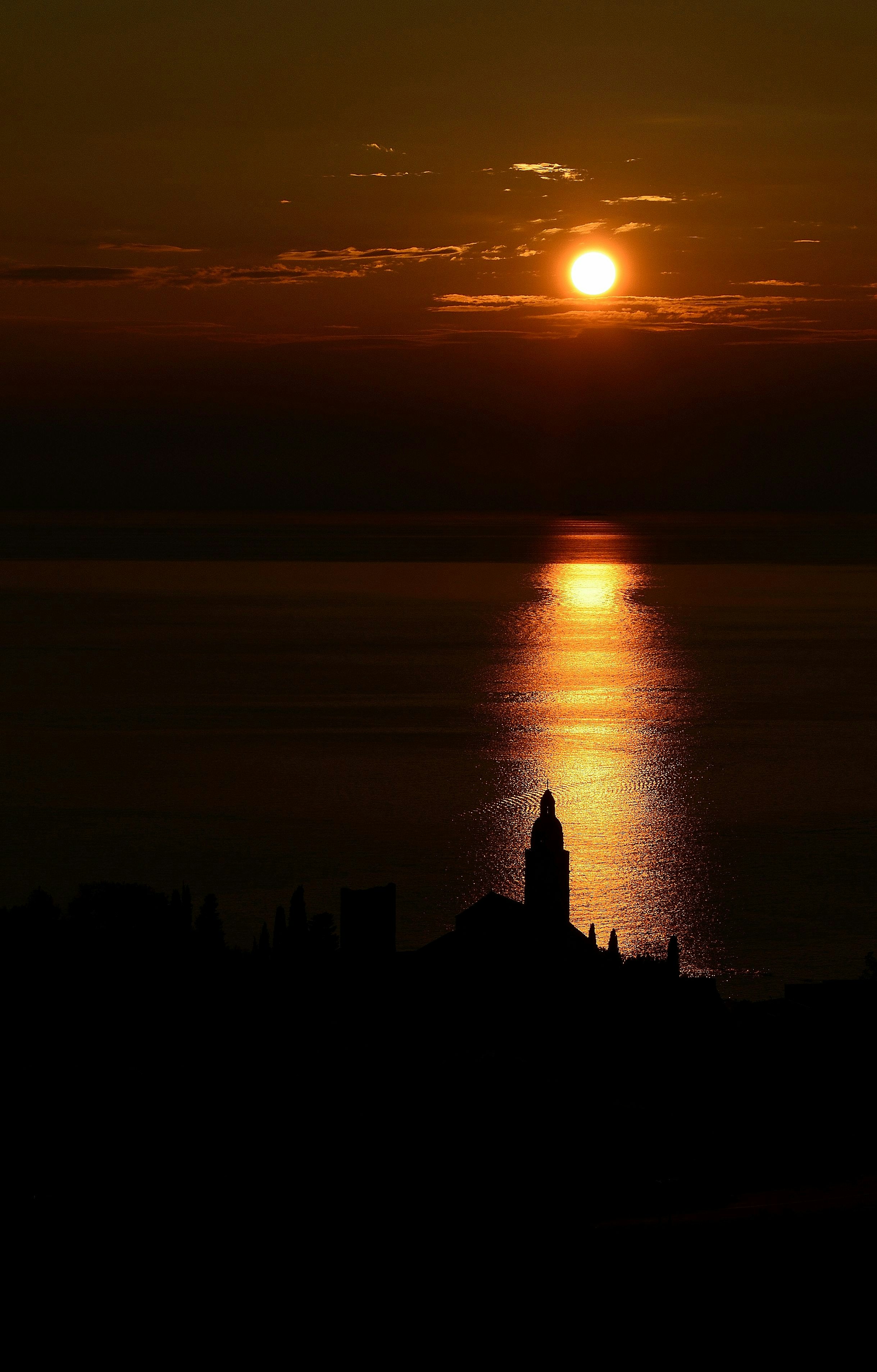 Gilded Horizon: Sunlit Silhouette Over Calm Water