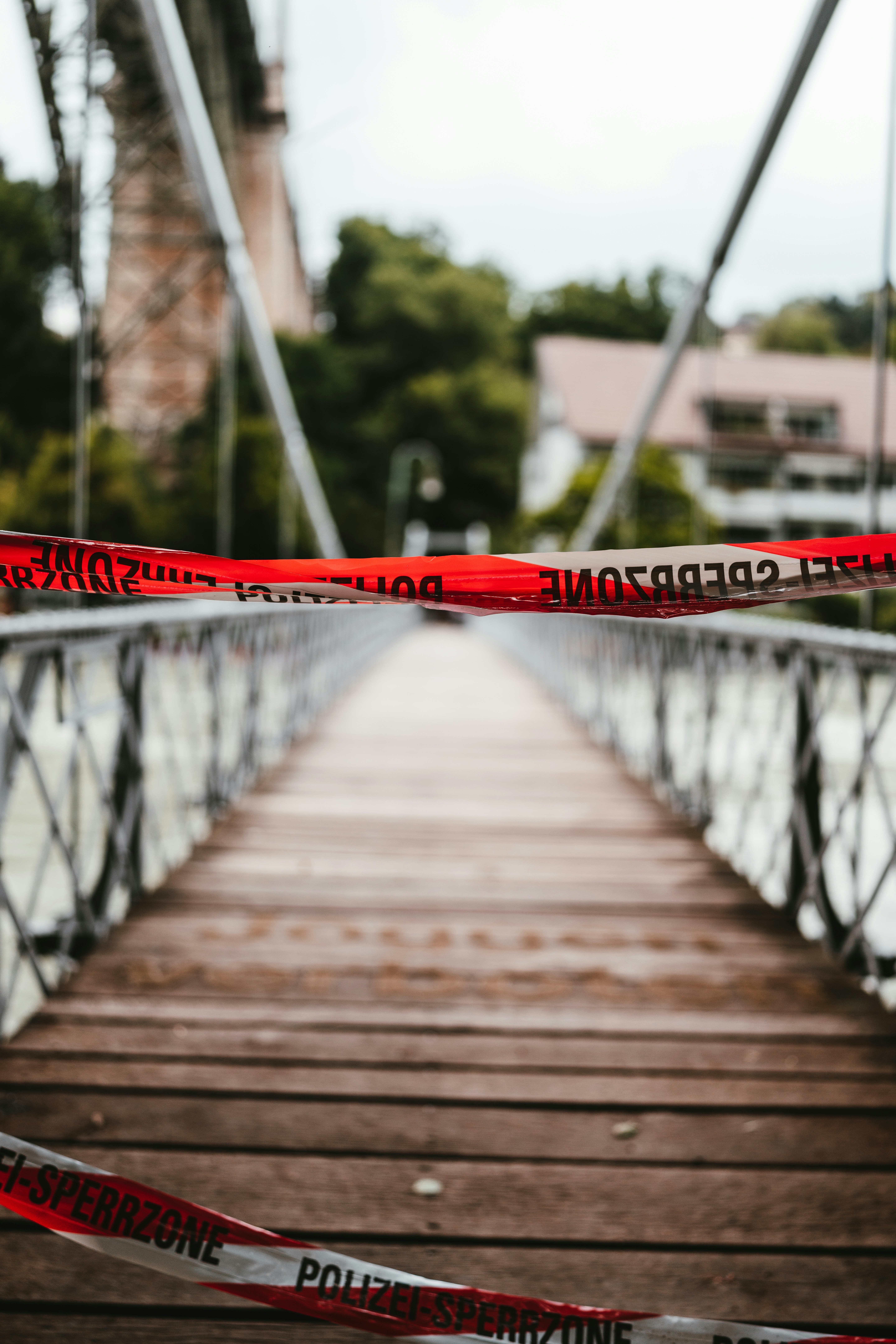 Crimson Barrier: Caution Tape Across a Narrow Bridge