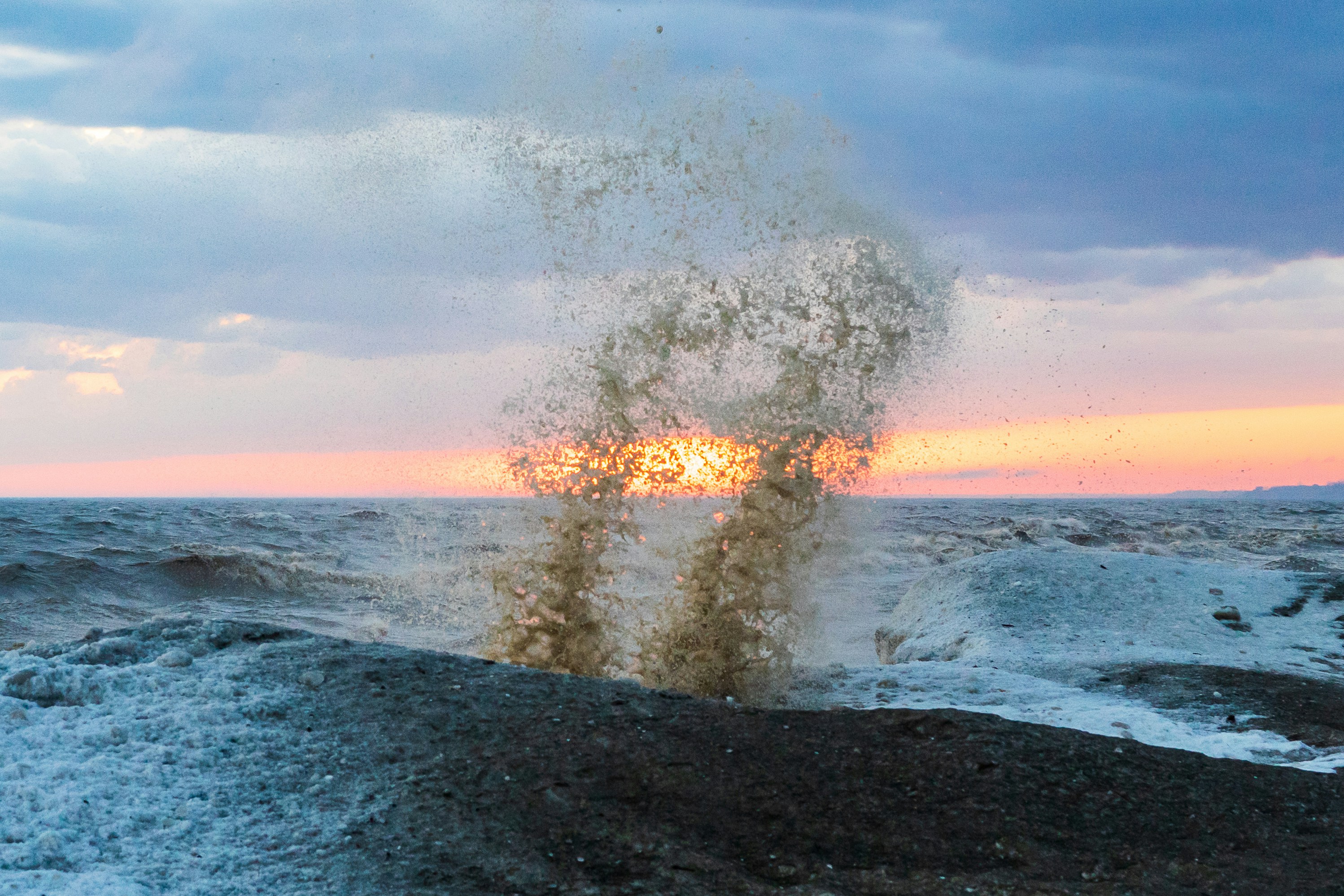 Sunset Break on a Lava Shore: Sea Spray Arches Over Dark Rock