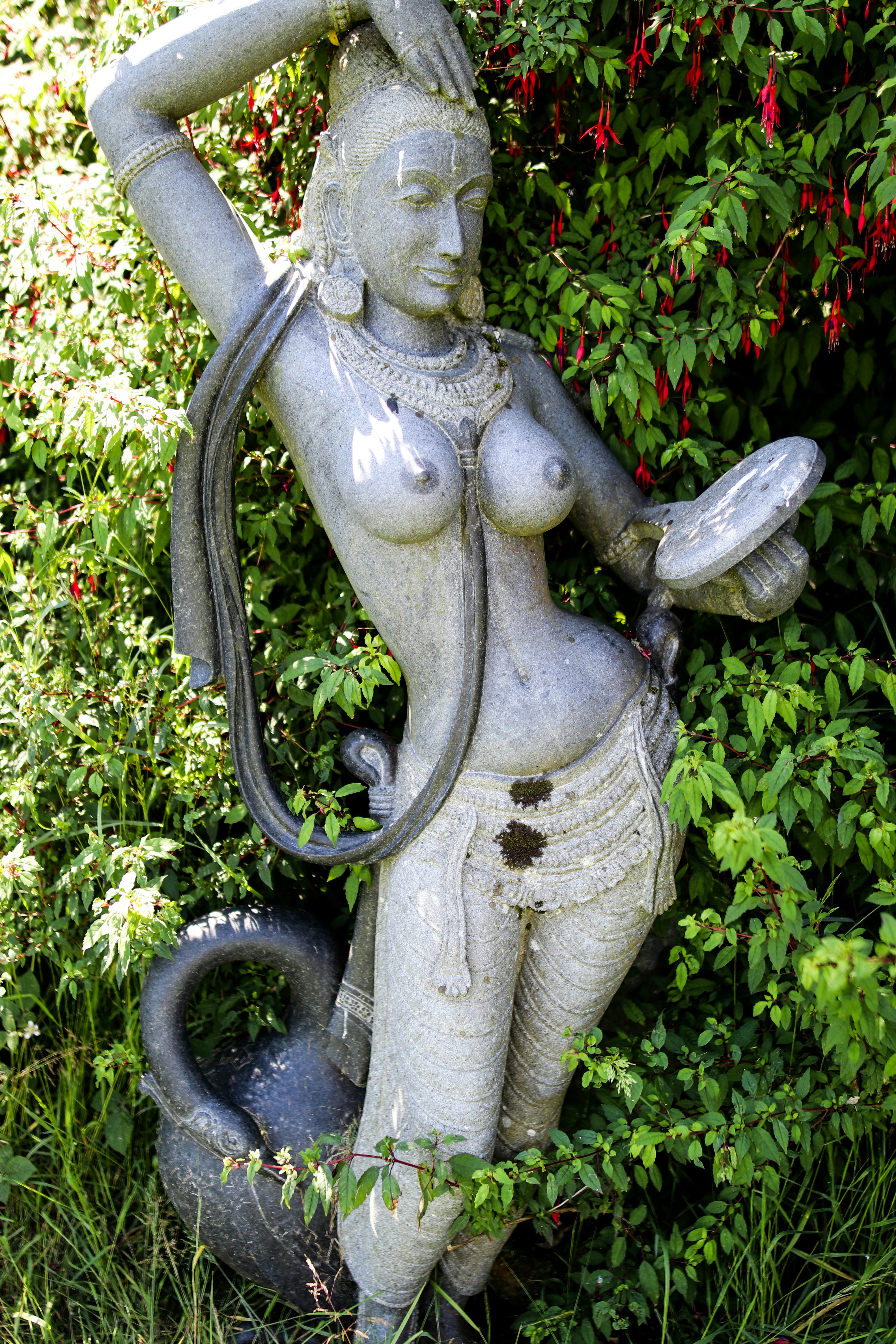 Stone Garden Siren in Verdant Light: Weathered Statue Among Red Foliage