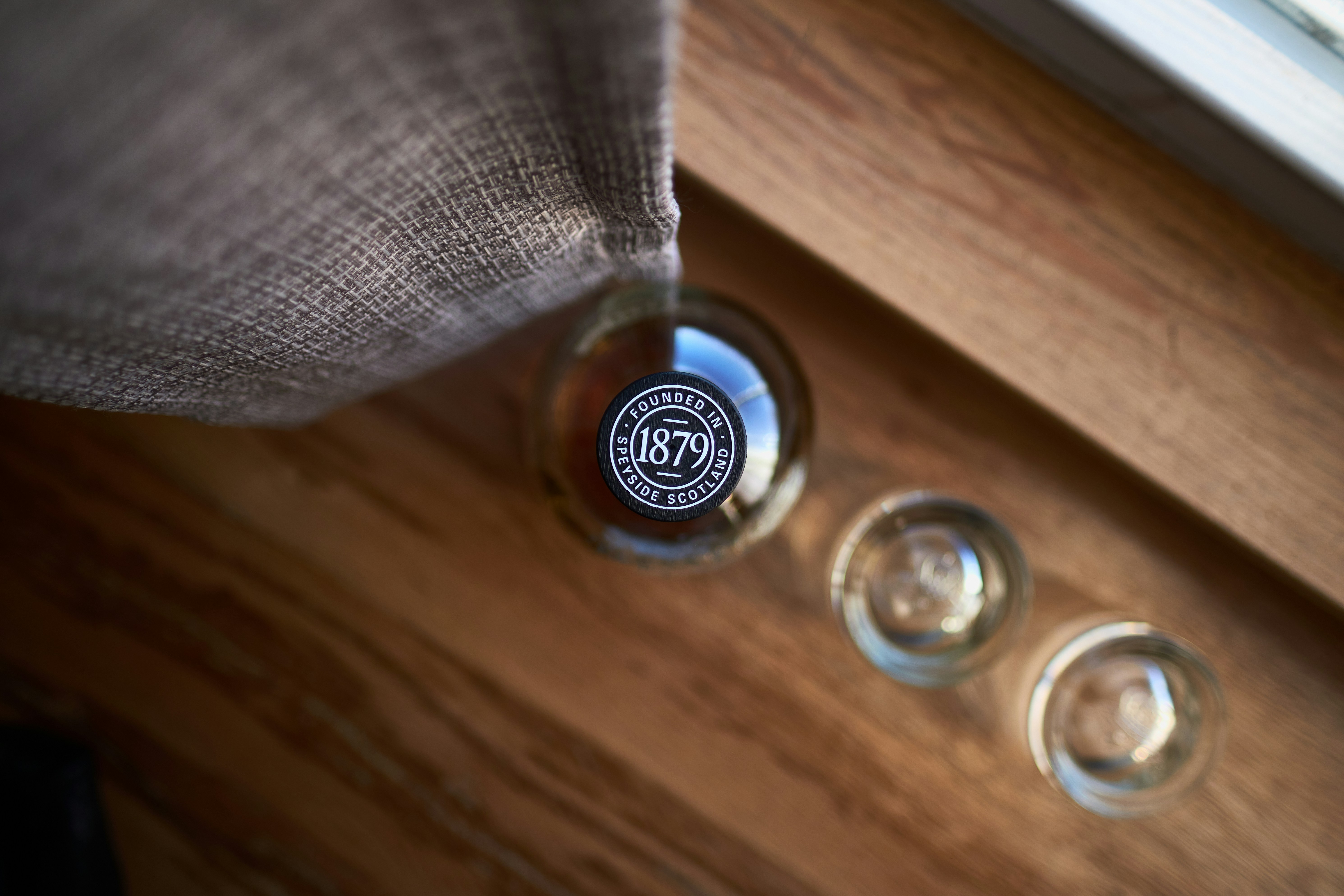 Top-Down Spirits: A Bottle and Its Glasses on a Wooden Stage
