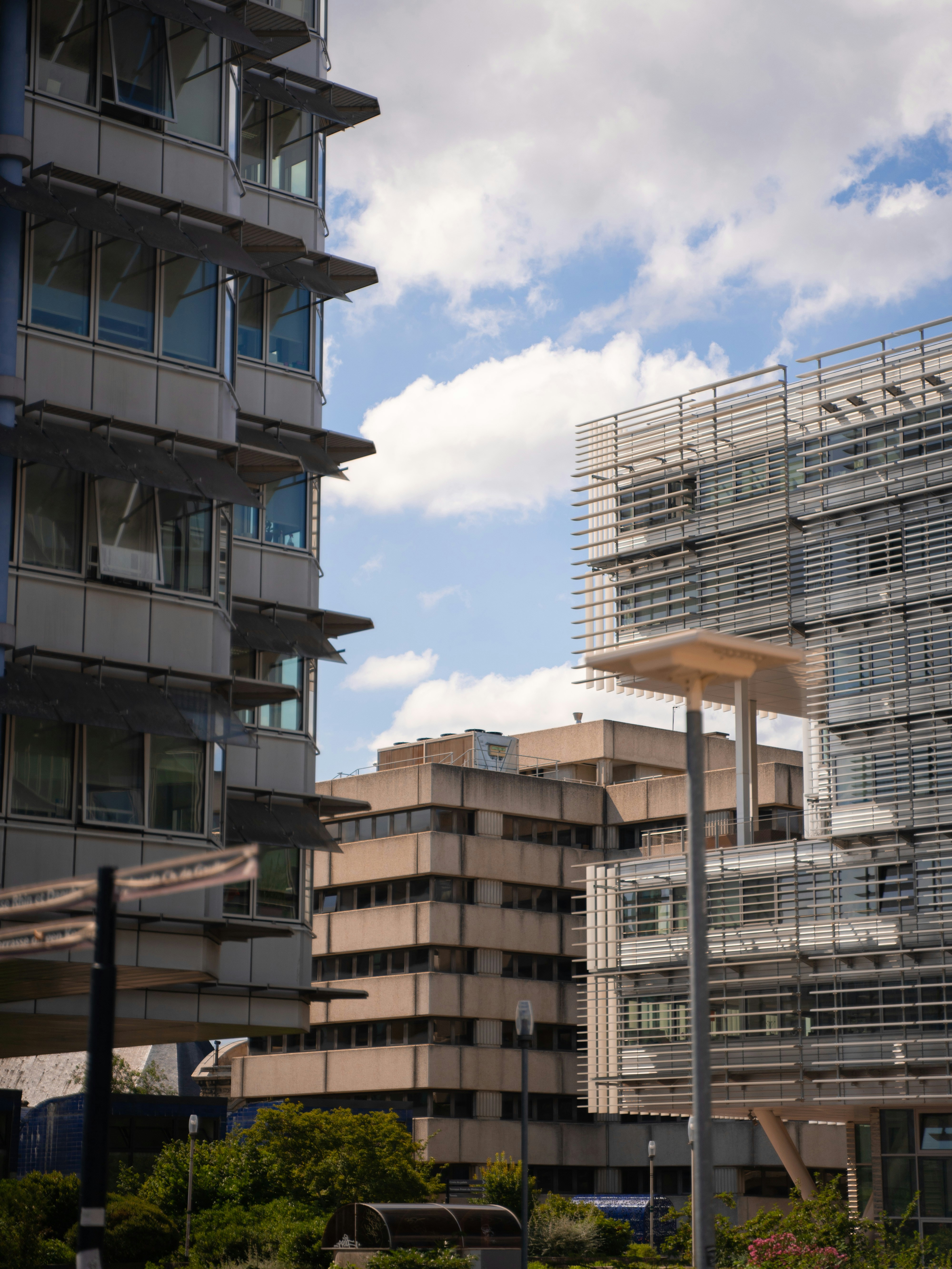 Contemporary buildings with glass facades and layered designs juxtaposed against a cloudy sky, showcasing innovative urban architecture.