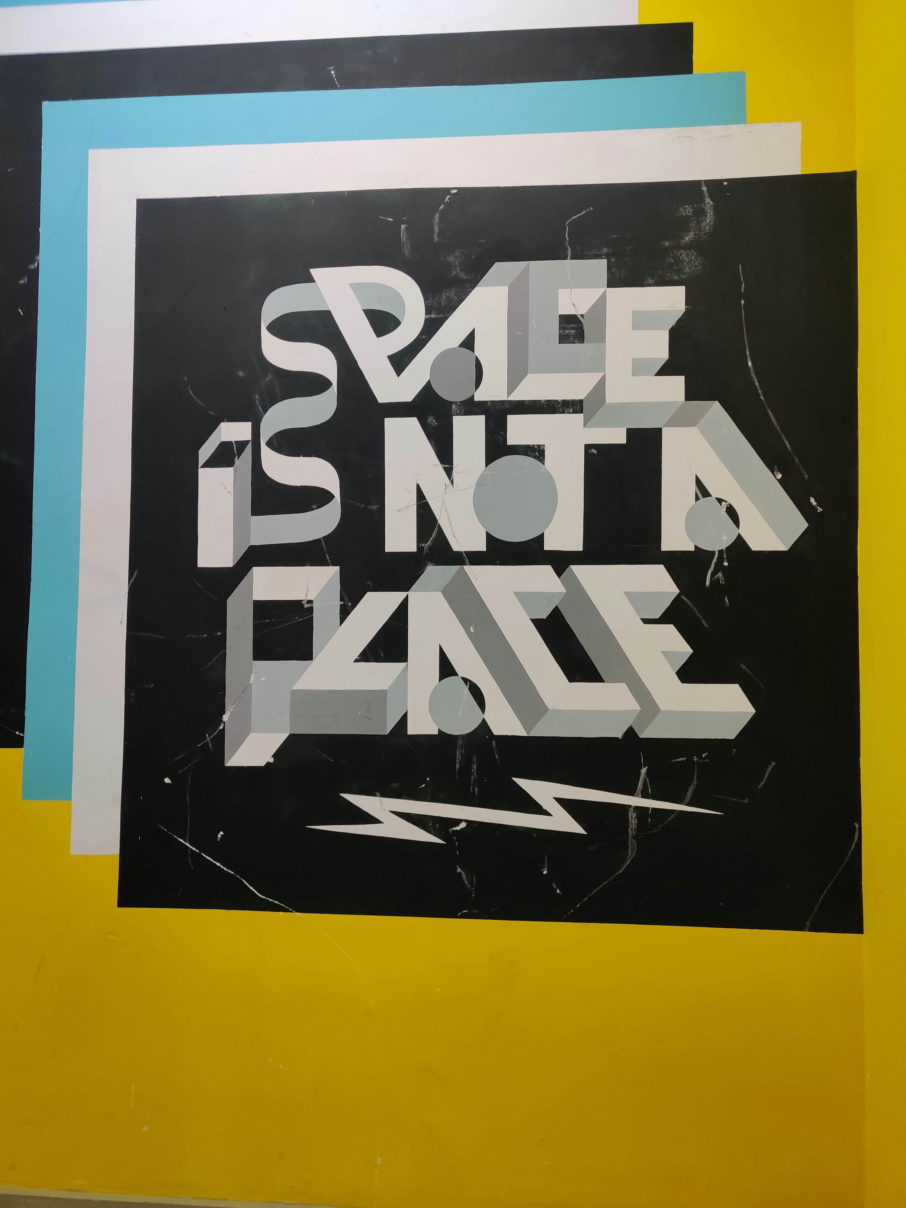 Colorful stacked posters frame a bold black square with geometric typography