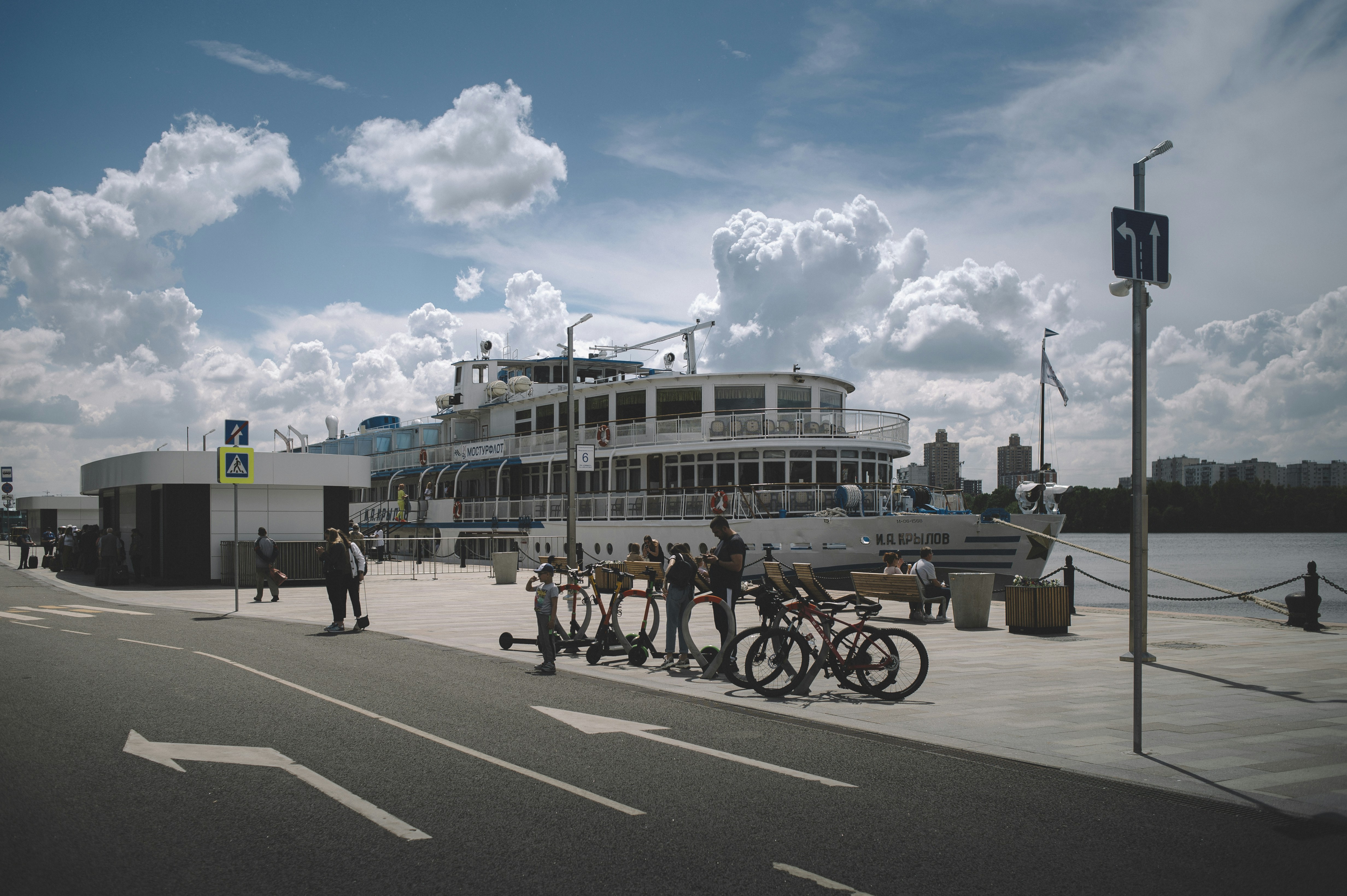 Dockside Reverie: Bicycles and a Riverboat Under Clouded Sky