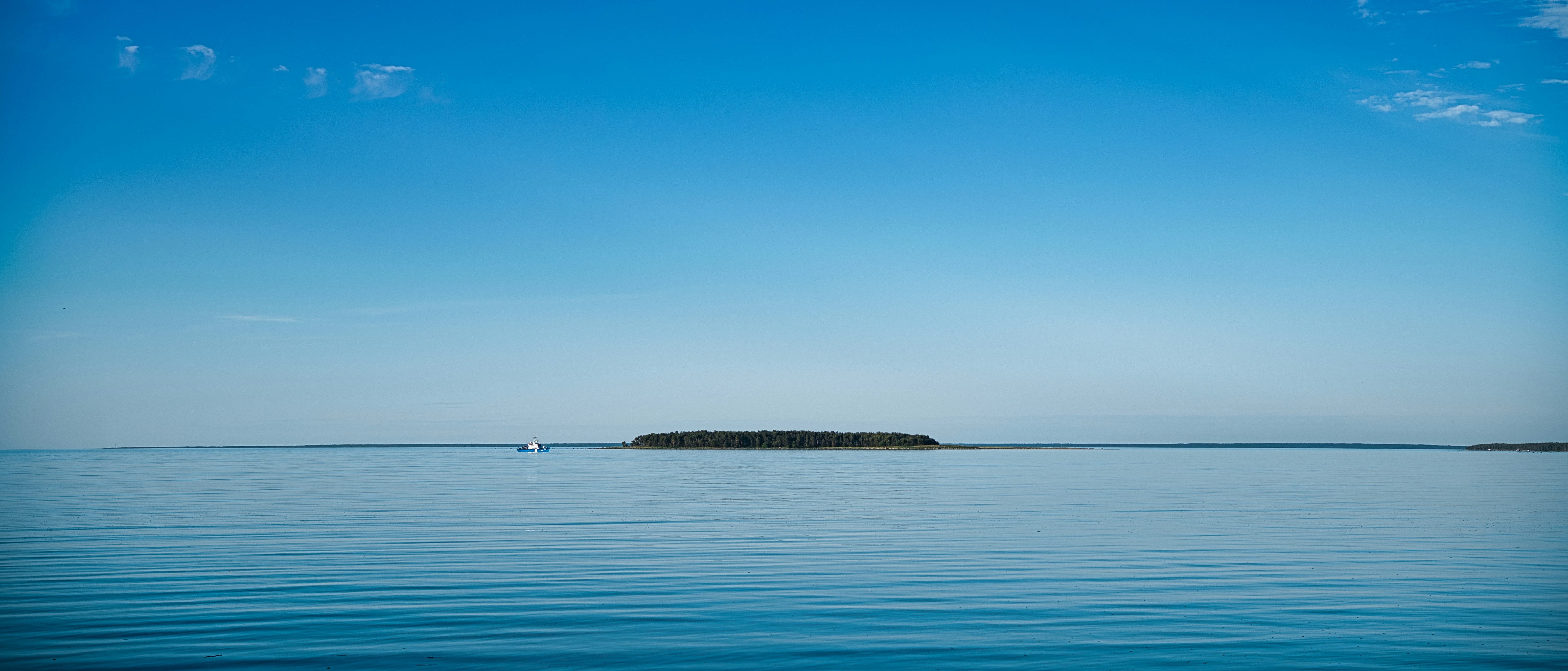 Calm waters stretching to a distant island under a clear blue sky. The scene conveys a sense of peace and isolation.