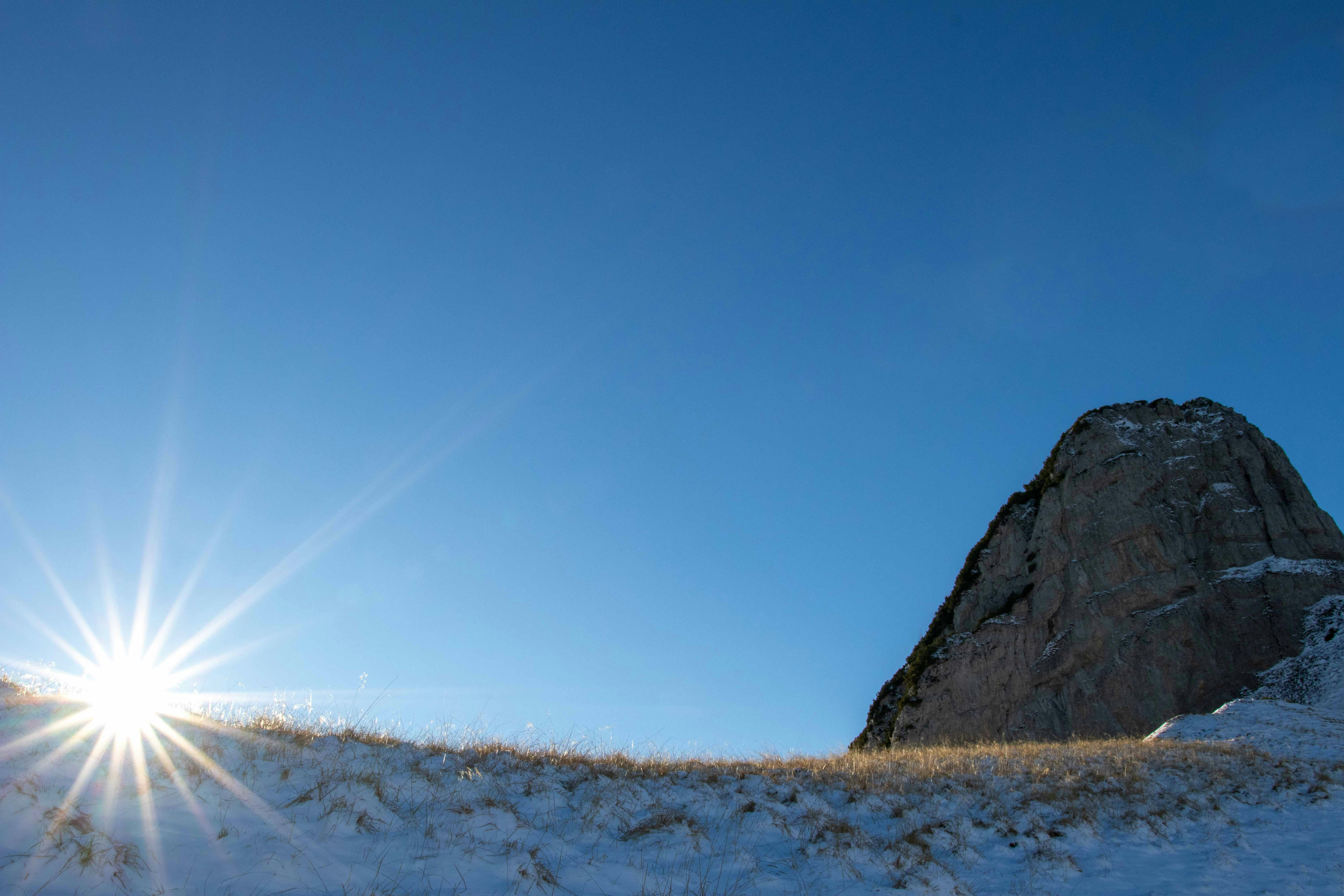 Sunburst on a Snow-Covered Slope Framing a Rugged Peak