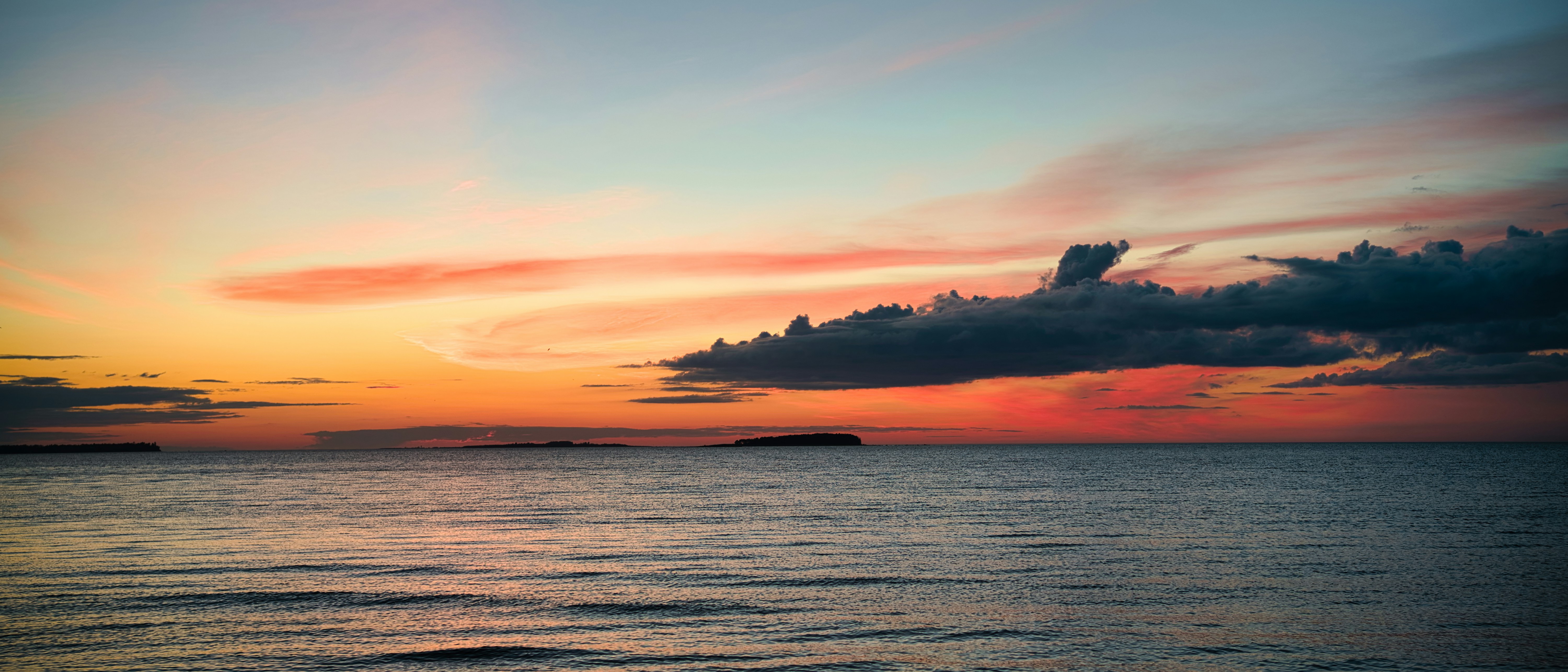 Serene sunset over a tranquil ocean, with vibrant hues reflecting on the water's surface.