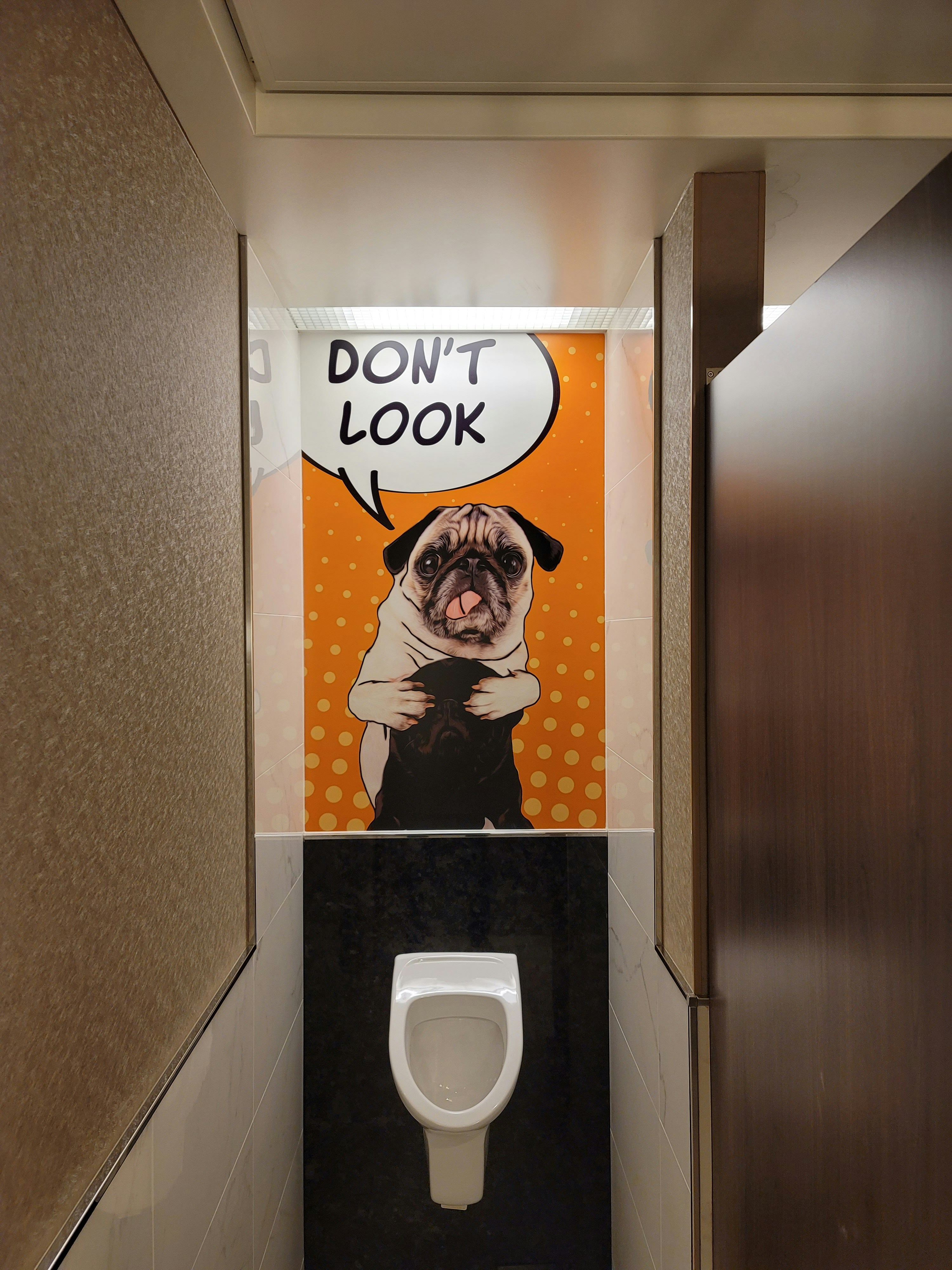 Humorous illustration of a pug holding a sign that says 'DON'T LOOK' in a restroom setting, with a vibrant orange background.
