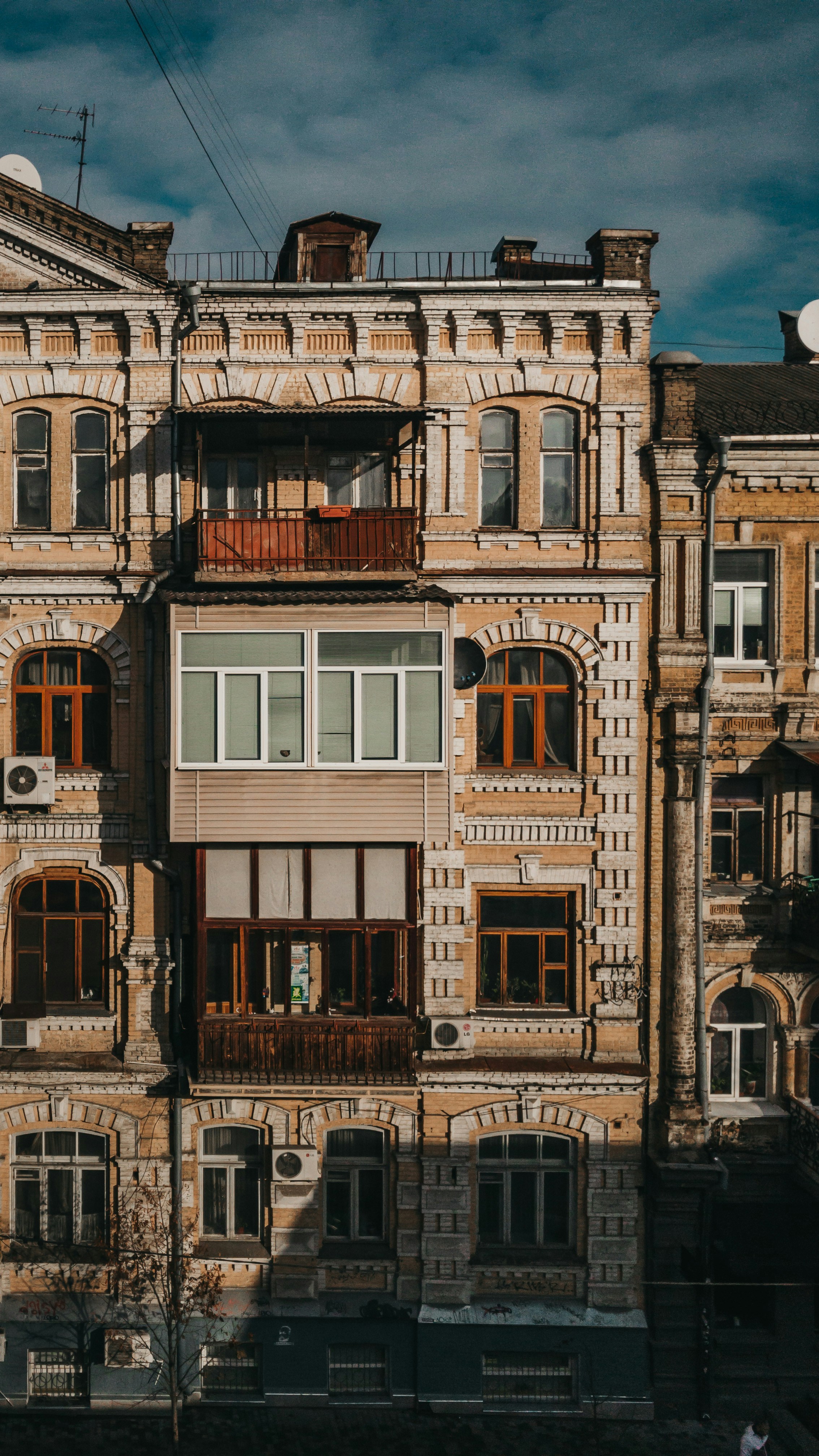 Historic building facade showcasing intricate designs and modern balcony addition. The juxtaposition highlights the blend of old and new architectural styles.