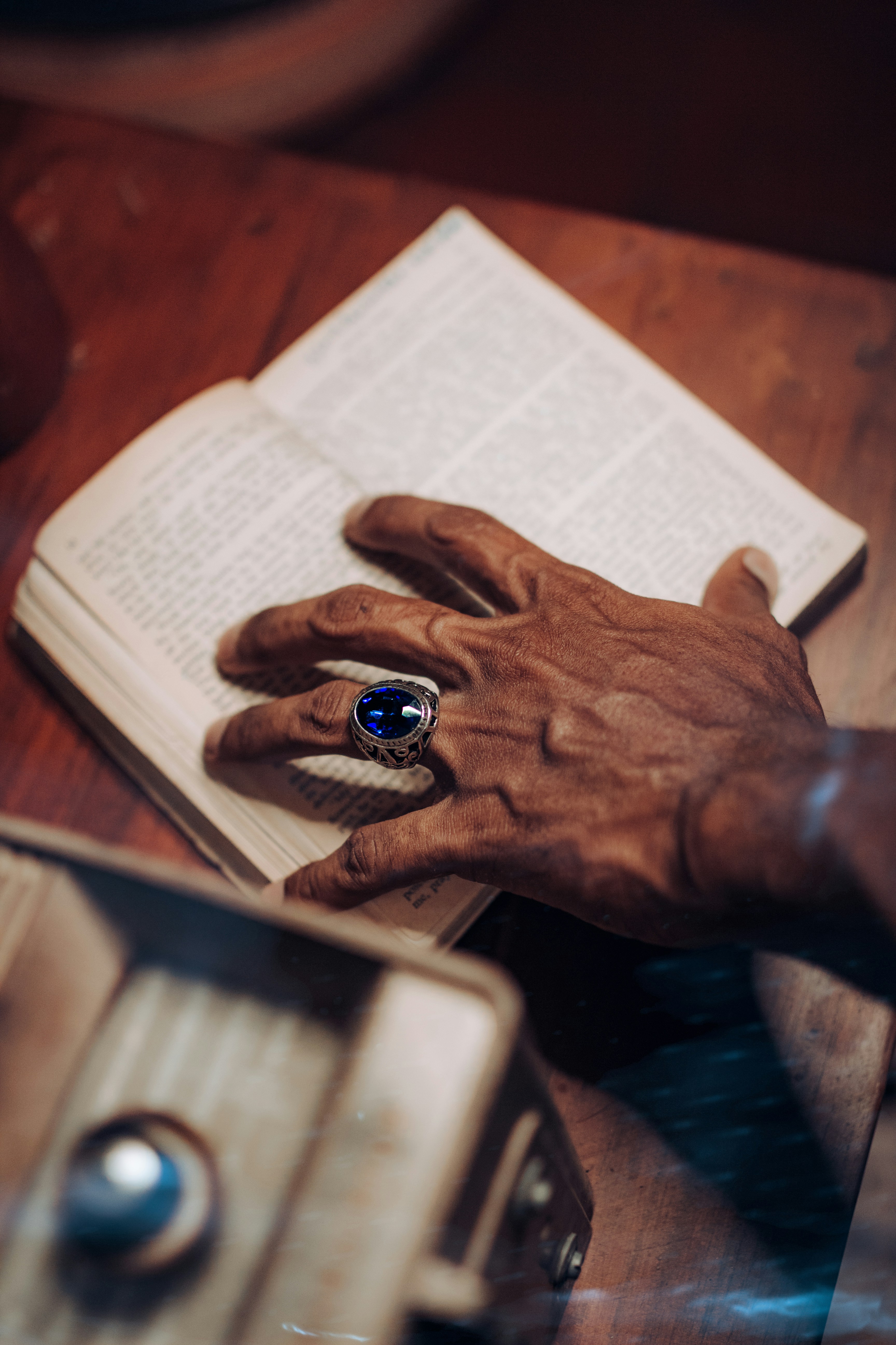 Azure Ring on Old Hands: A Quiet Moment over the Open Book