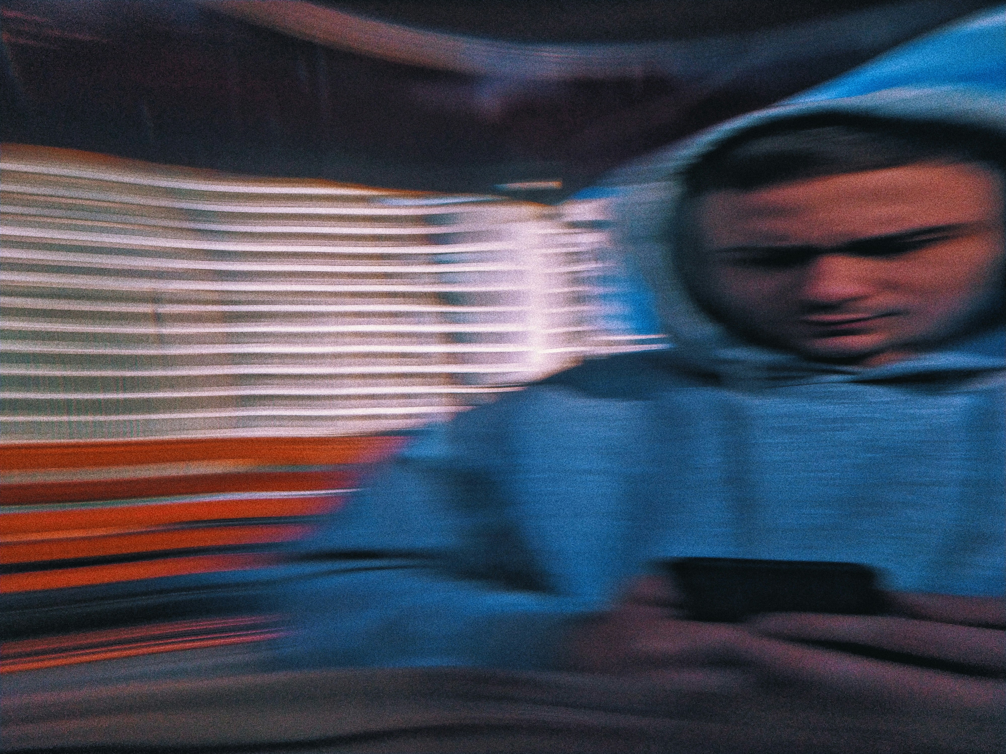 Person in a hoodie using a phone with streaked motion blur effect.