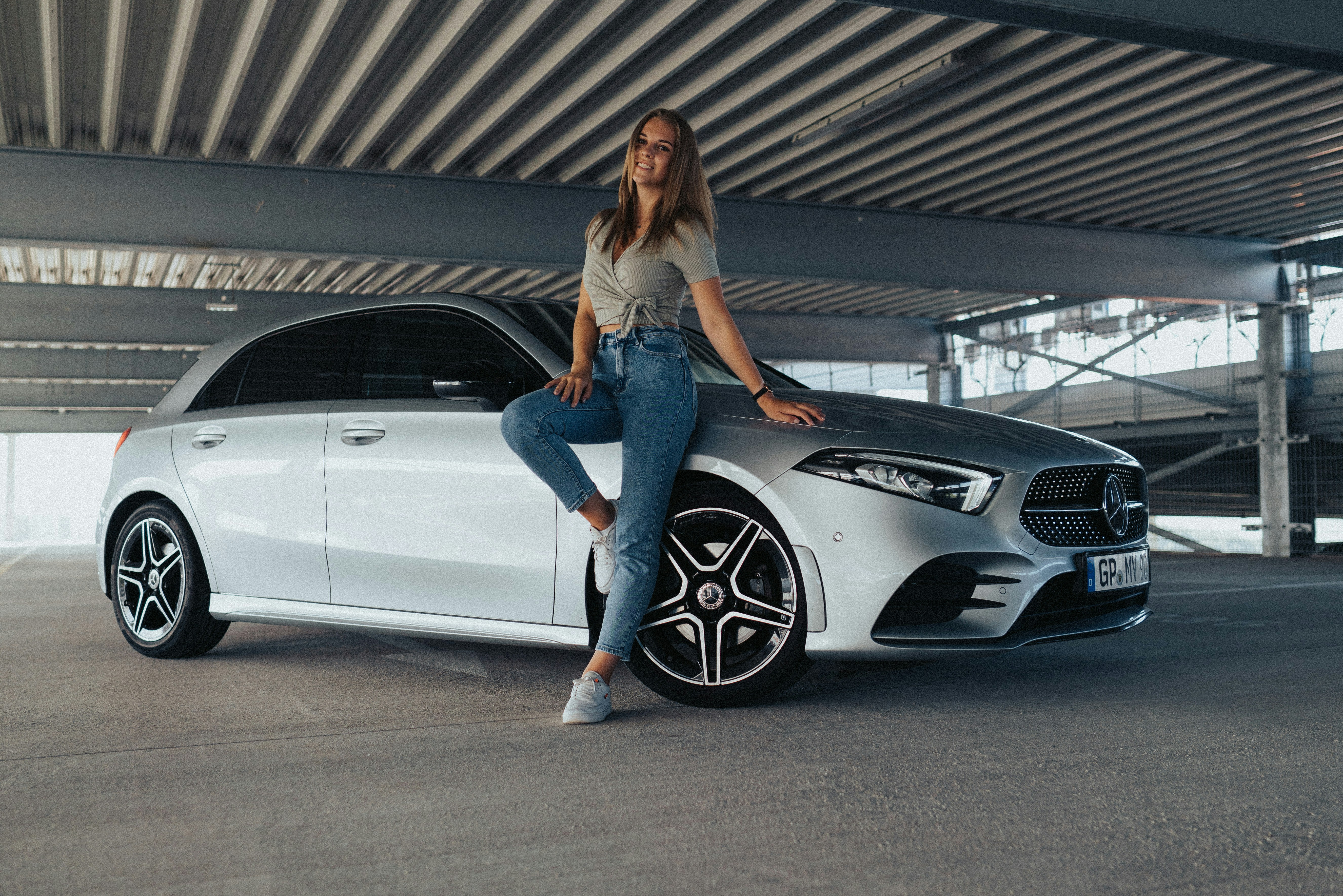 Under the Parking Garage Canopy: A poised figure beside a white Mercedes