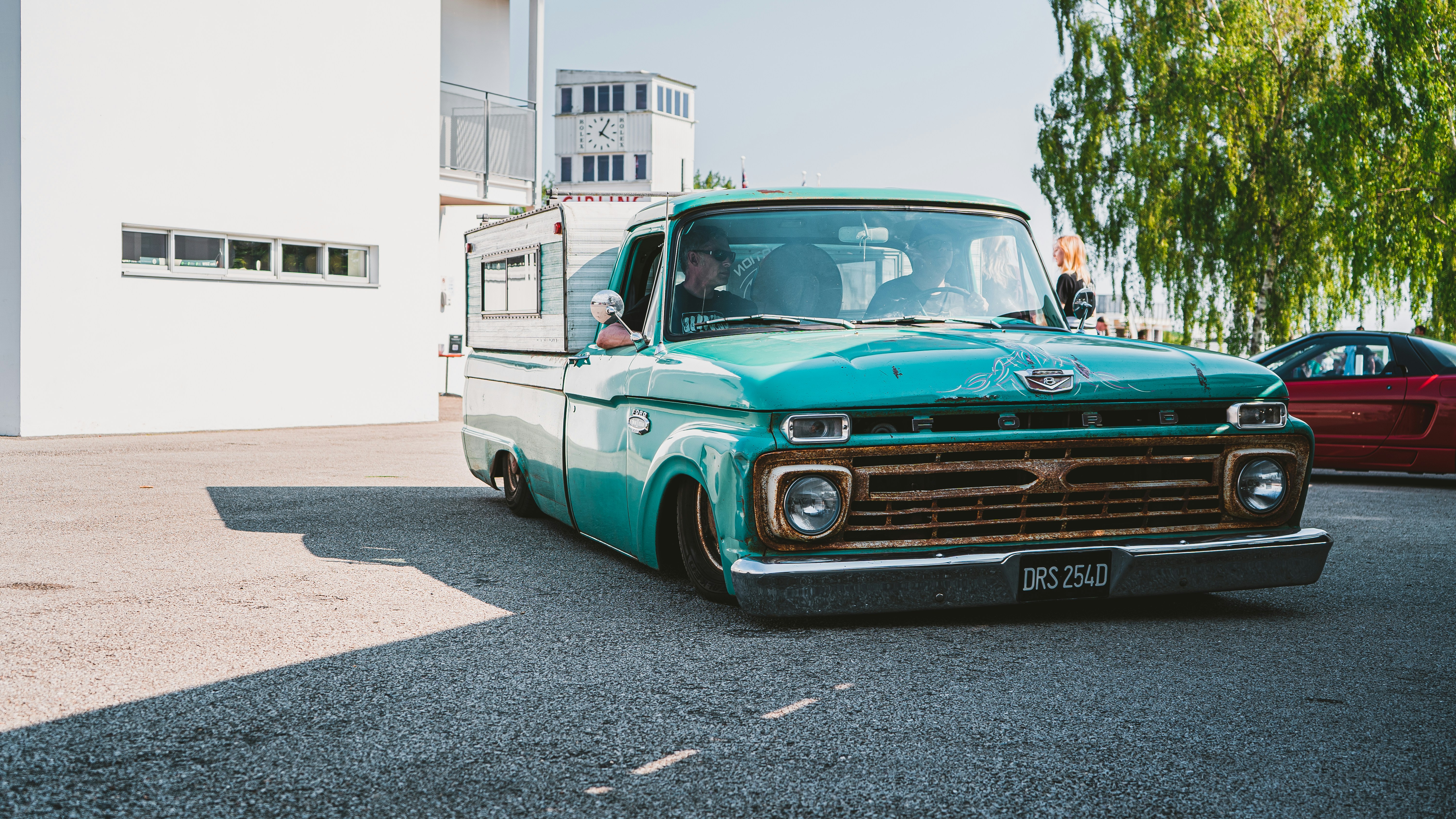 Classic turquoise pickup truck parked in a modern setting, showcasing its vintage charm against contemporary architecture.
