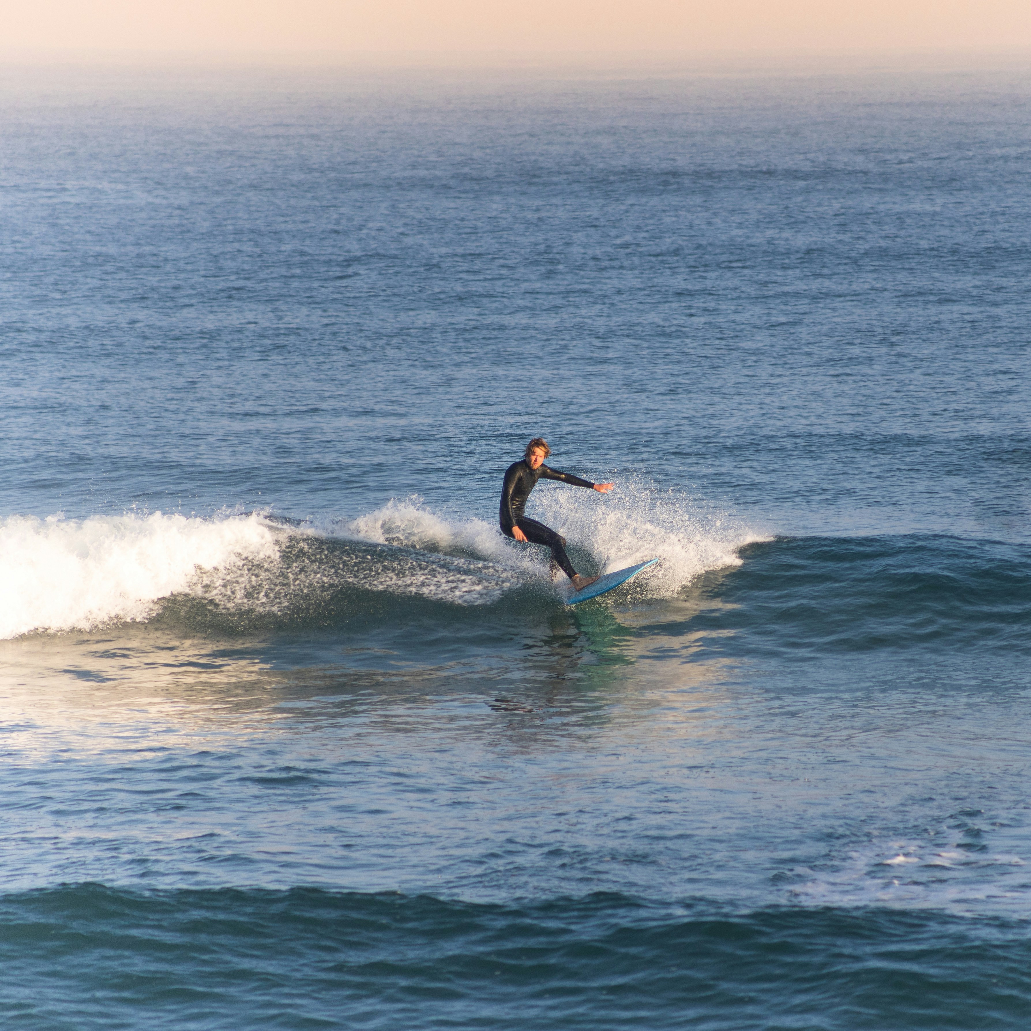 Surfer skillfully navigating a wave under a clear sky, showcasing the harmony between man and nature.