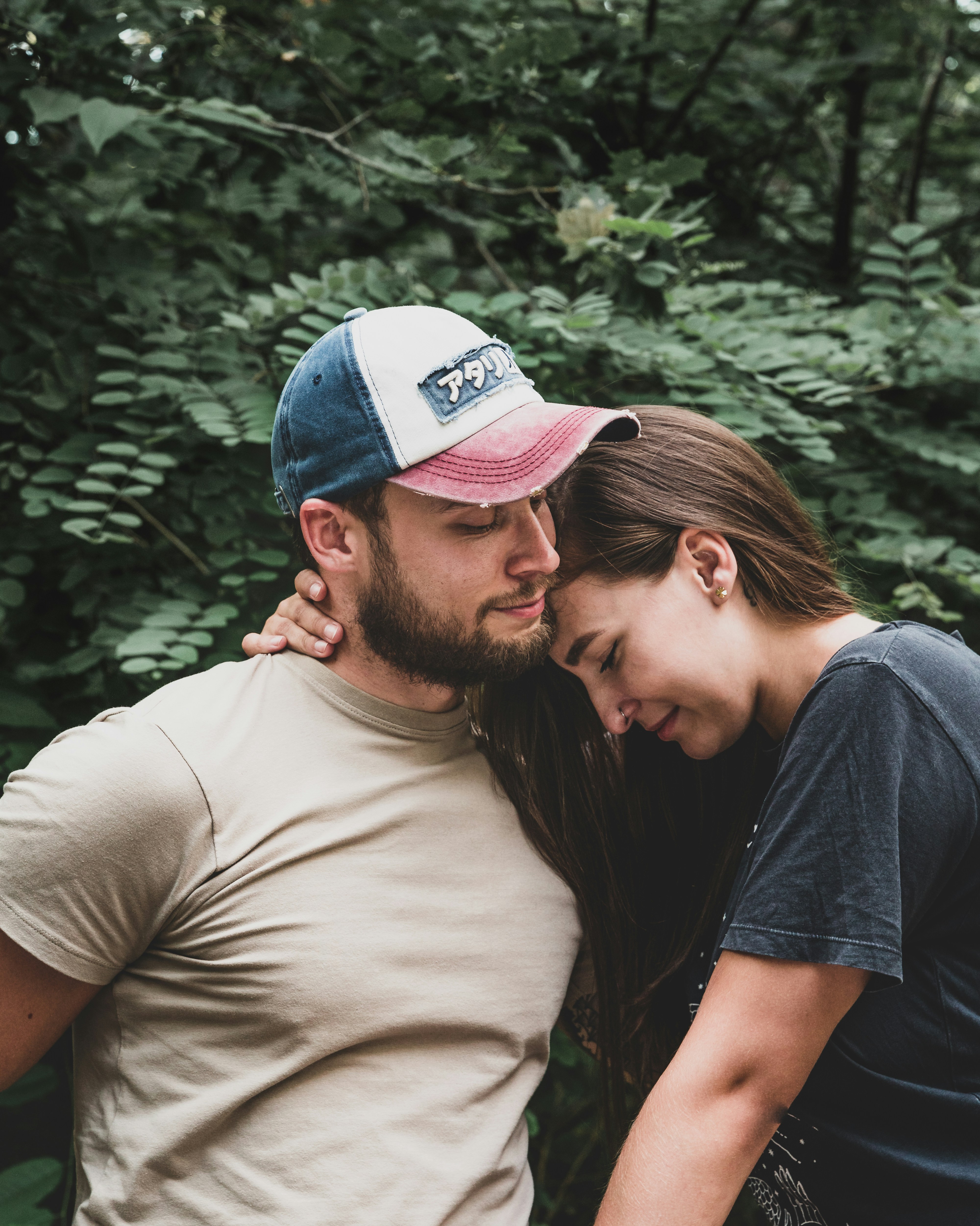 Couple sharing an intimate moment surrounded by lush greenery, showcasing their connection and affection.