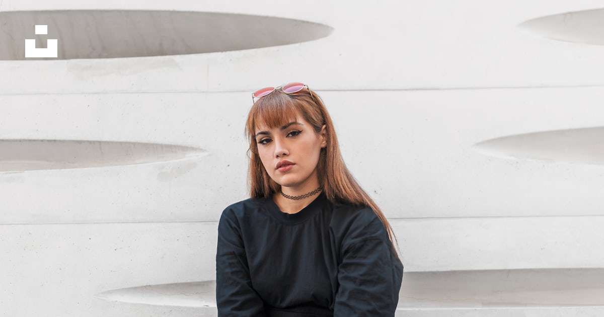 白いコンクリートの壁に座っている黒い長袖シャツと青いデニムジーンズの女性の写真 Unsplashのテヘランの無料画像